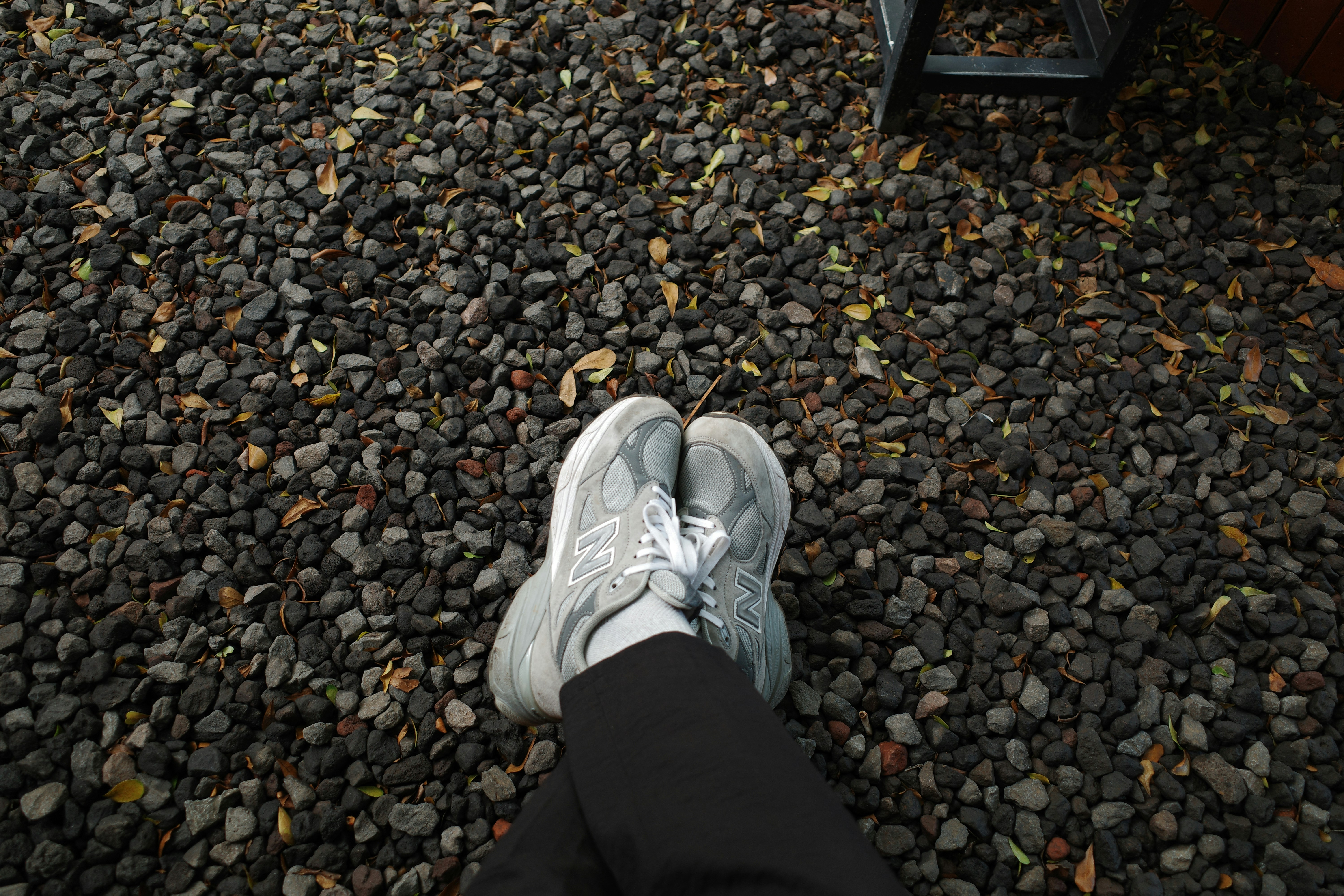 Feet in shoes rest on a gravel bed.