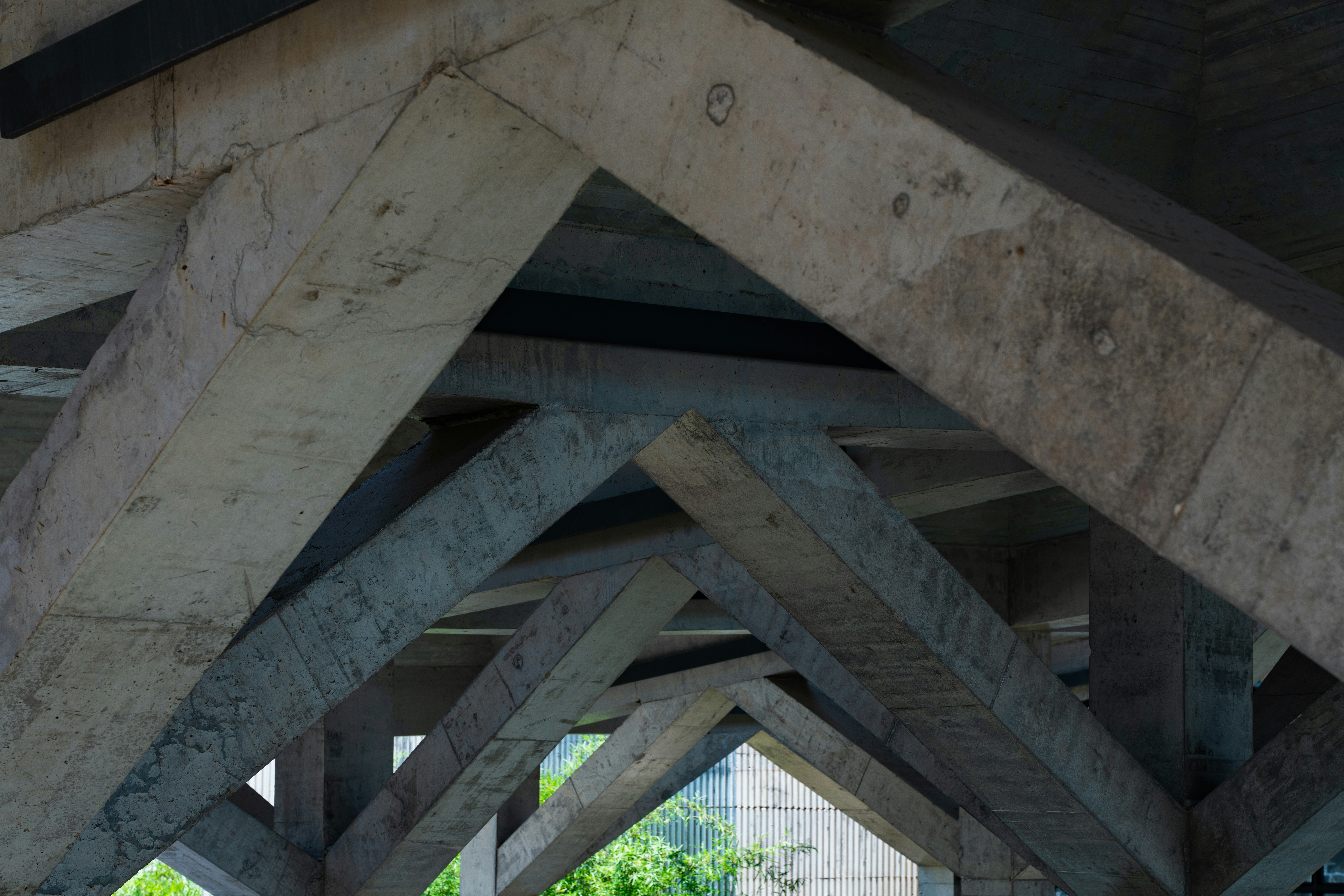 Abstract view of intersecting concrete beams beneath a structure, showcasing architectural design and shadow play.