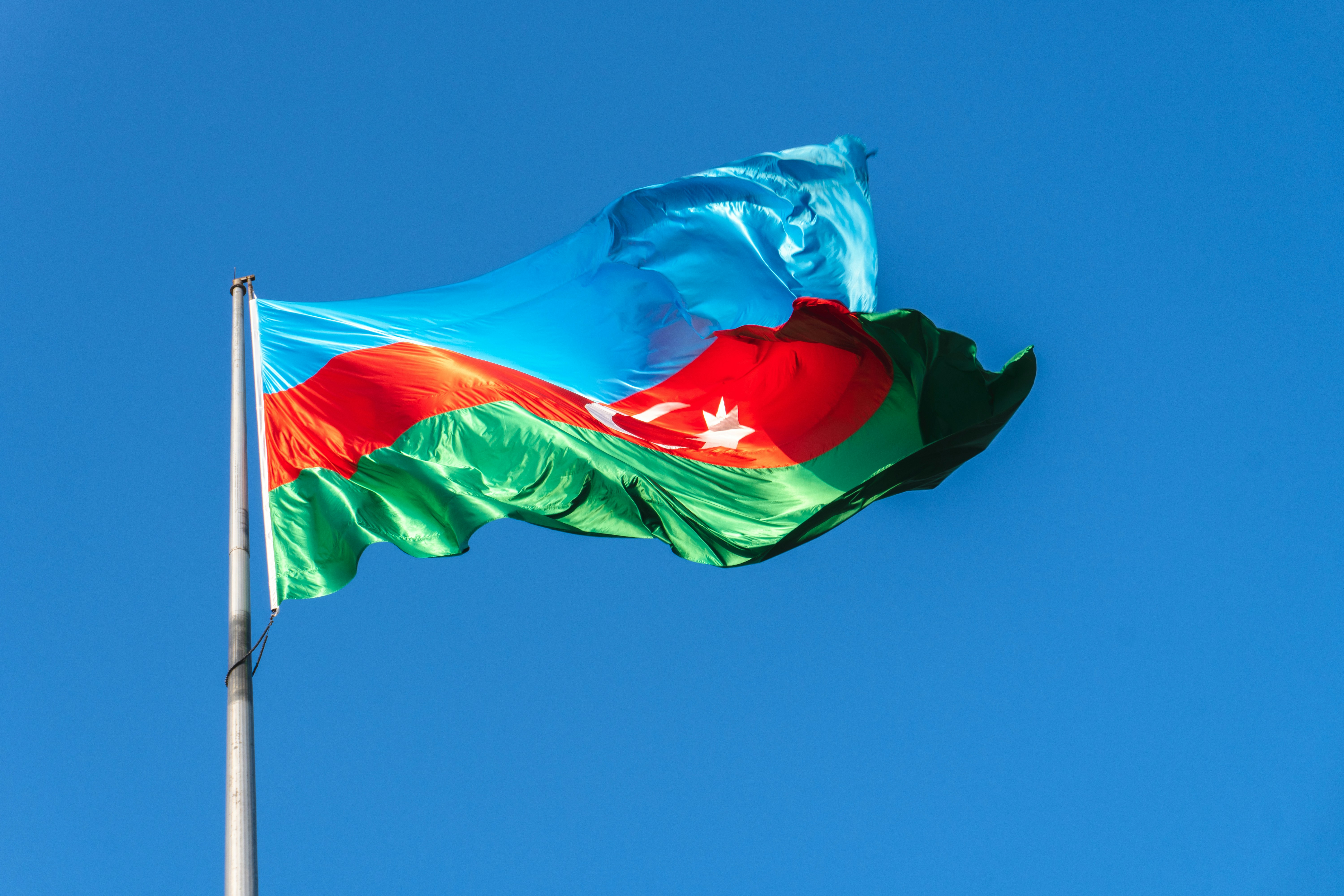 Azerbaijan flag | The azerbaijani flag waves against a clear, blue sky.