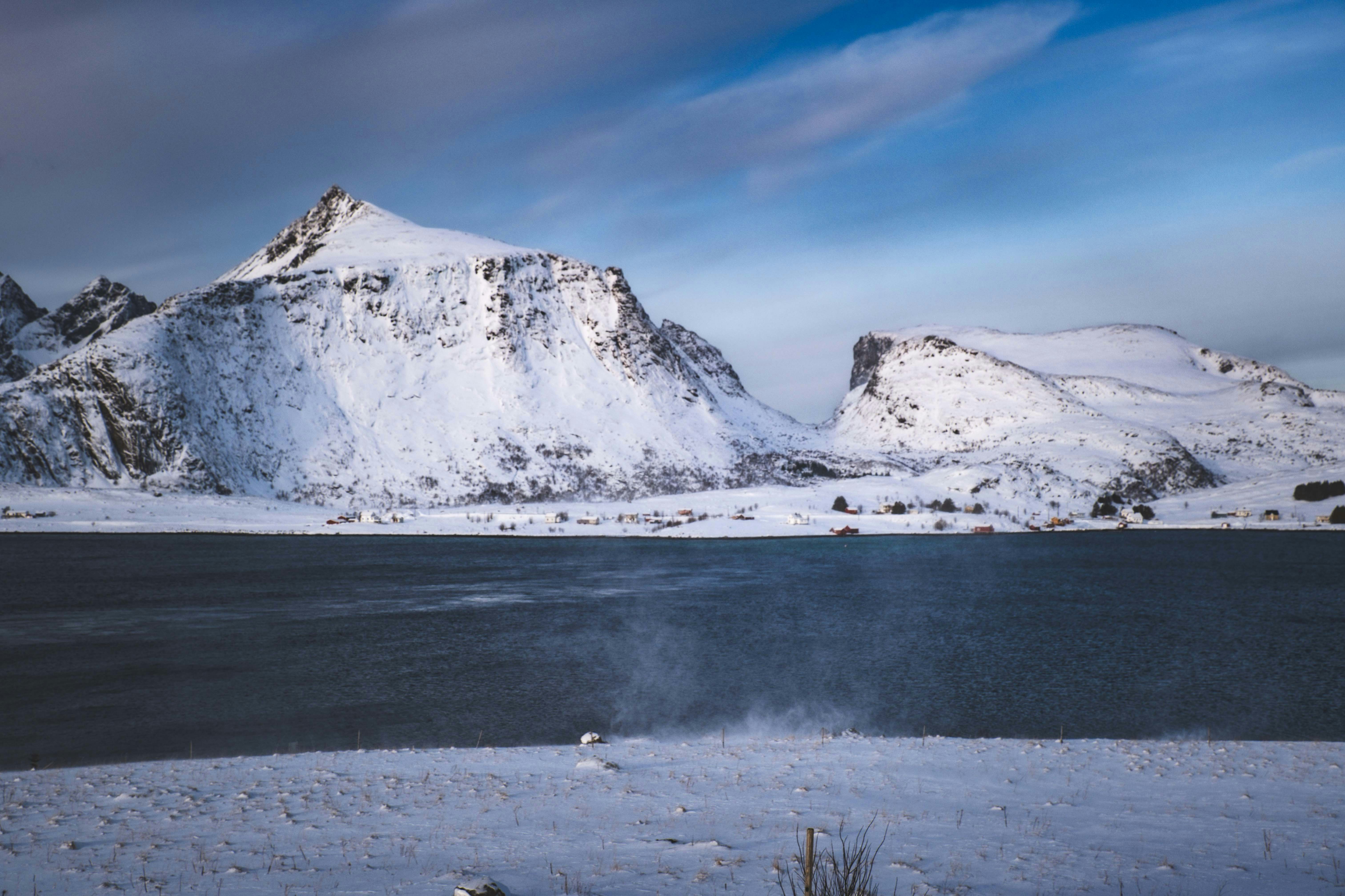 Snow-covered mountains border a serene body of water.