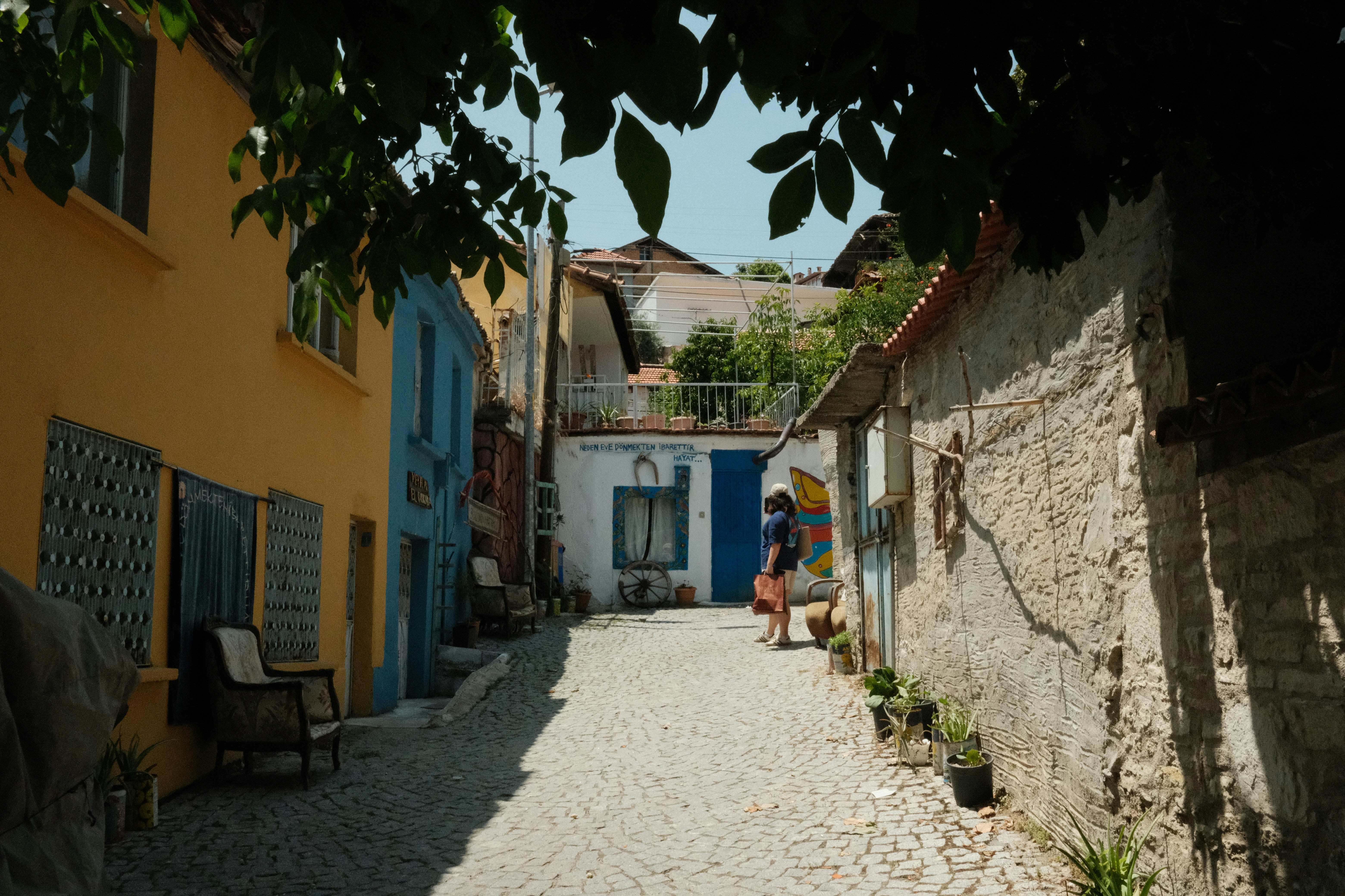 A narrow, colorful street in a sunlit town.