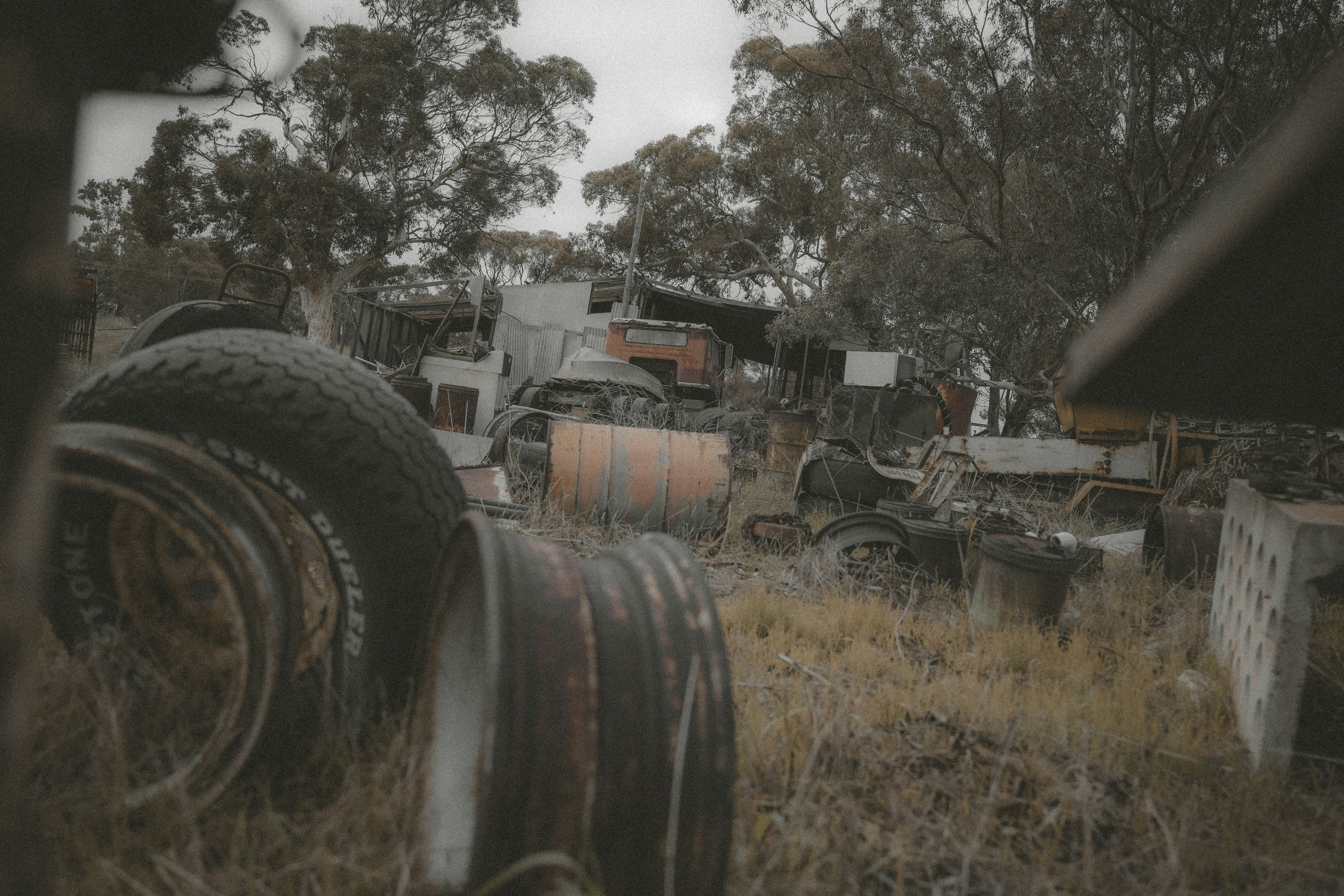 An array of discarded tires and rusted metal remnants scattered across a desolate landscape, hinting at a once-busy site now left to nature's embrace.