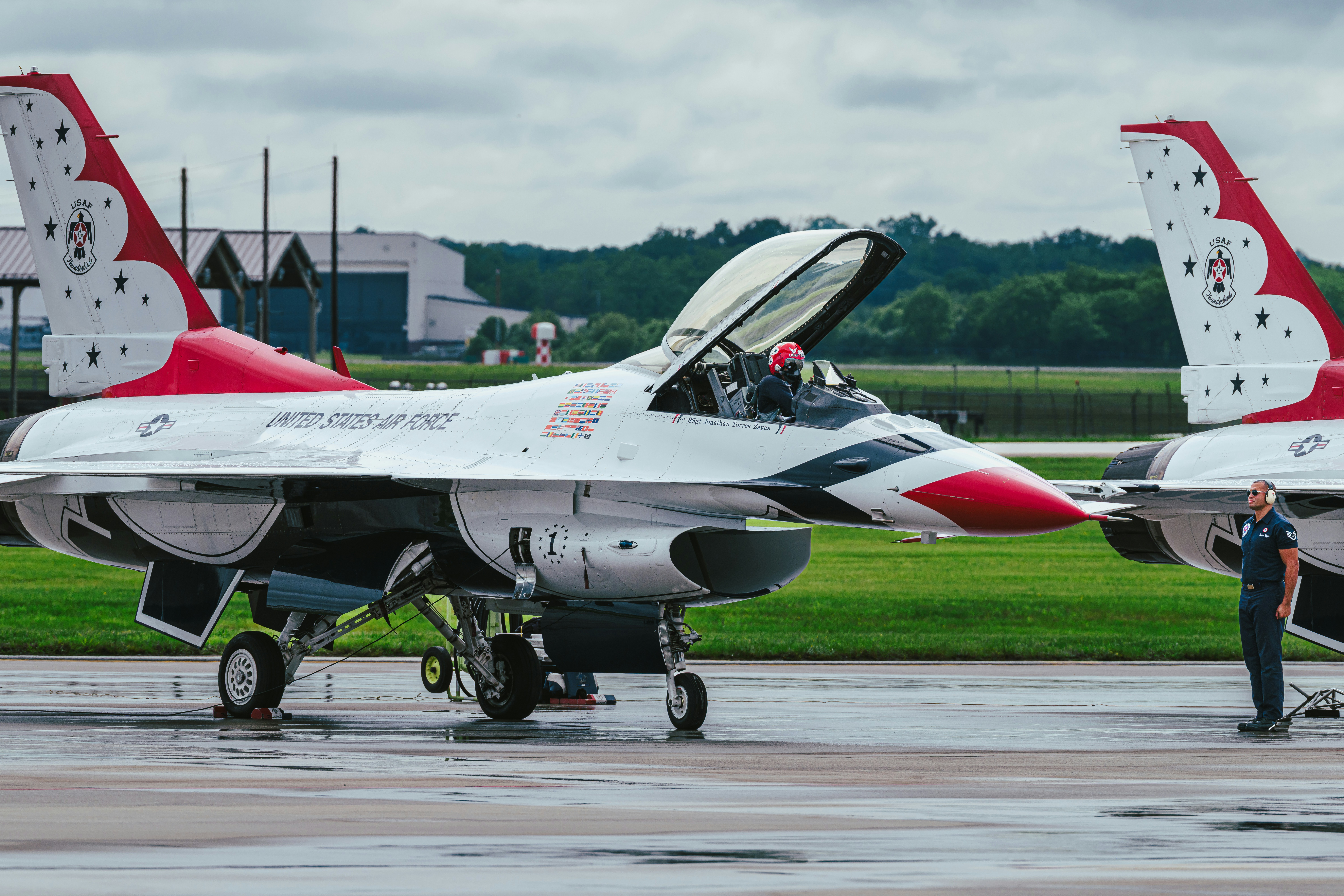 USAF Thunderbird F-16C with canopy open during ground operations at McGuire AFB, May 2025. Pilot and ground crew prepare for airshow demonstration. | The air force thunderbirds jet sits on the tarmac.