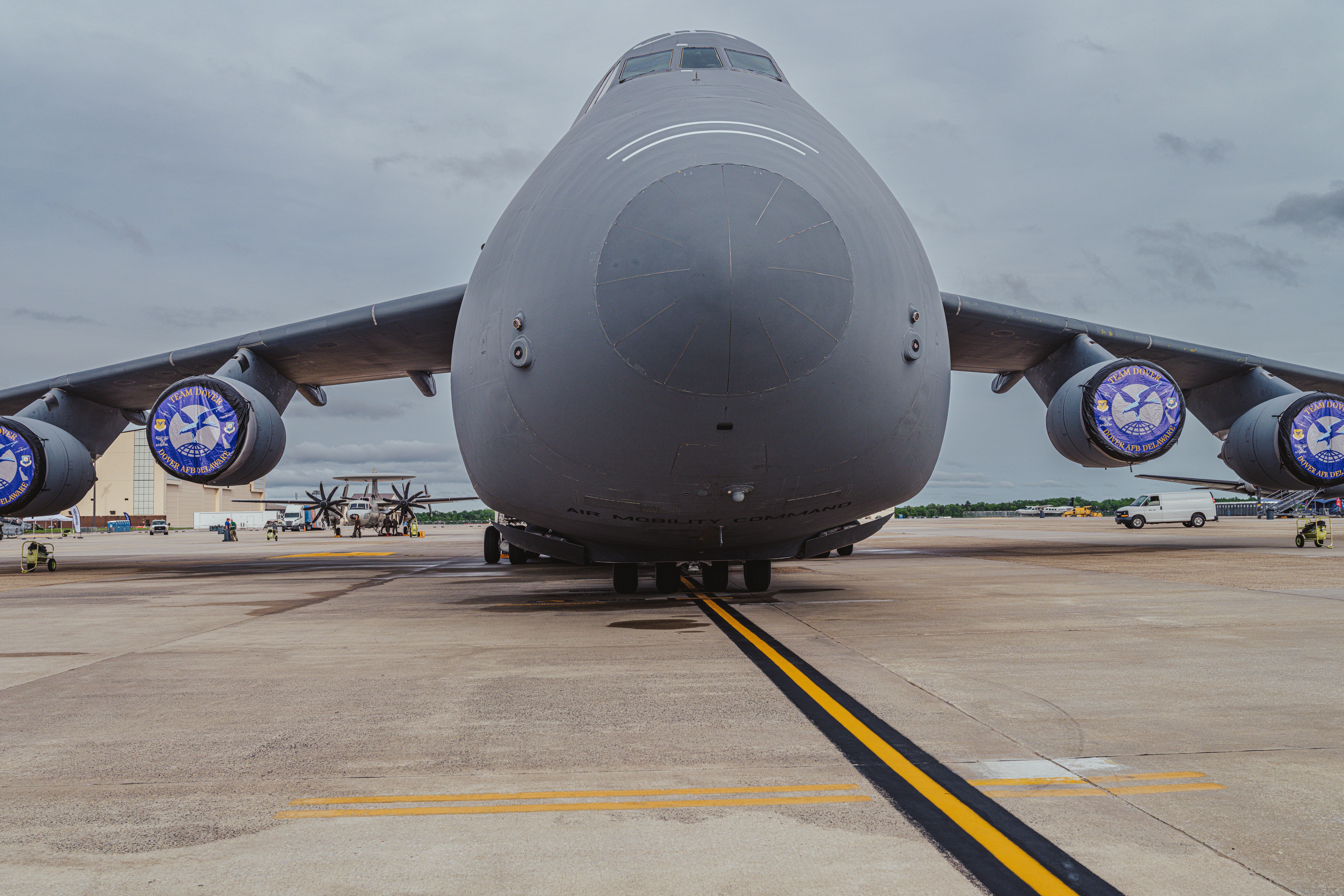 A head-on view of a C-5M Super Galaxy with “Team Dover – McGuire AFB” engine covers, photographed at McGuire Air Force Base, New Jersey, May 16th 2025. | A large airplane sits on the runway.