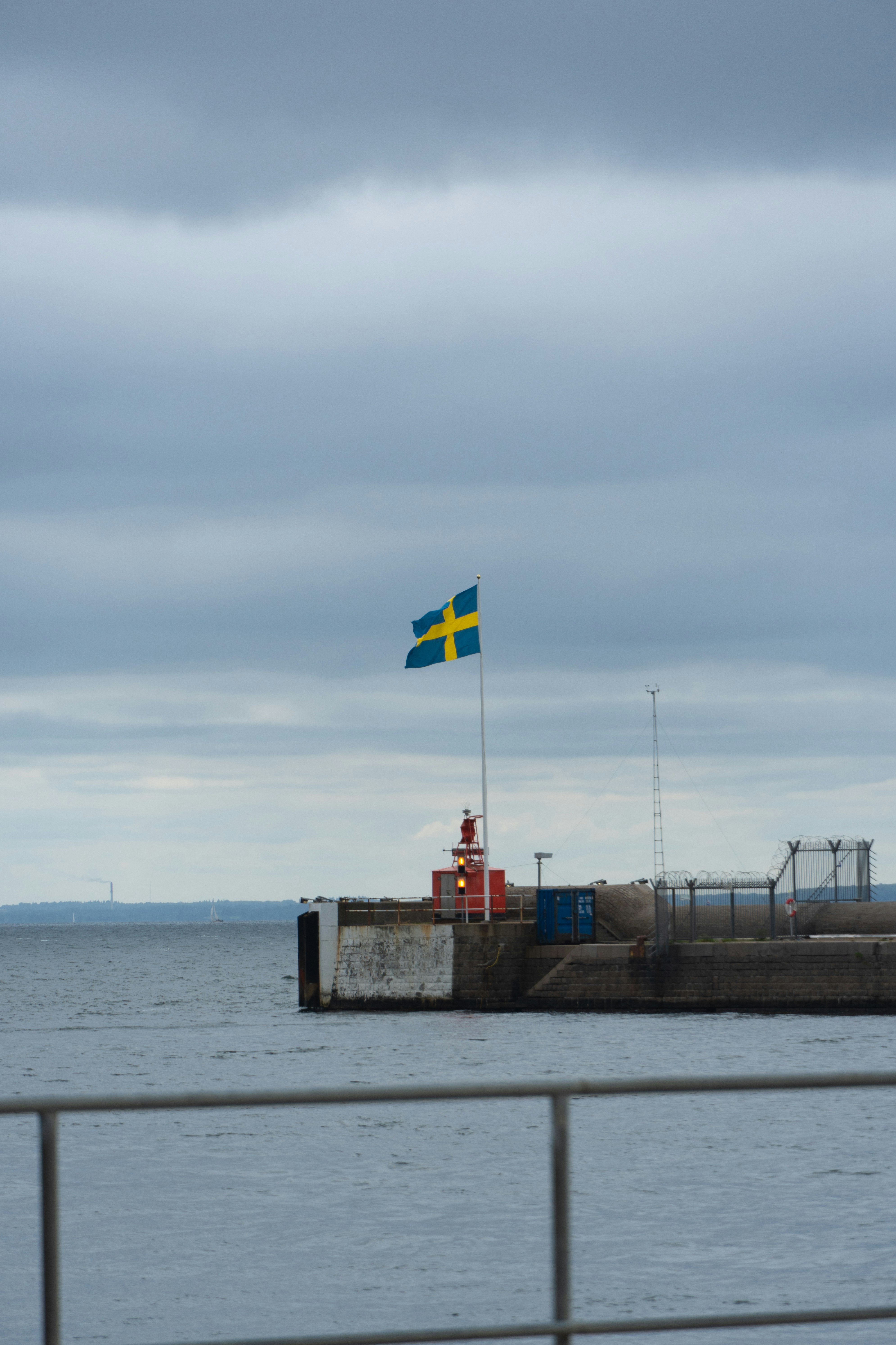 A swedish flag flies over a coastal structure.