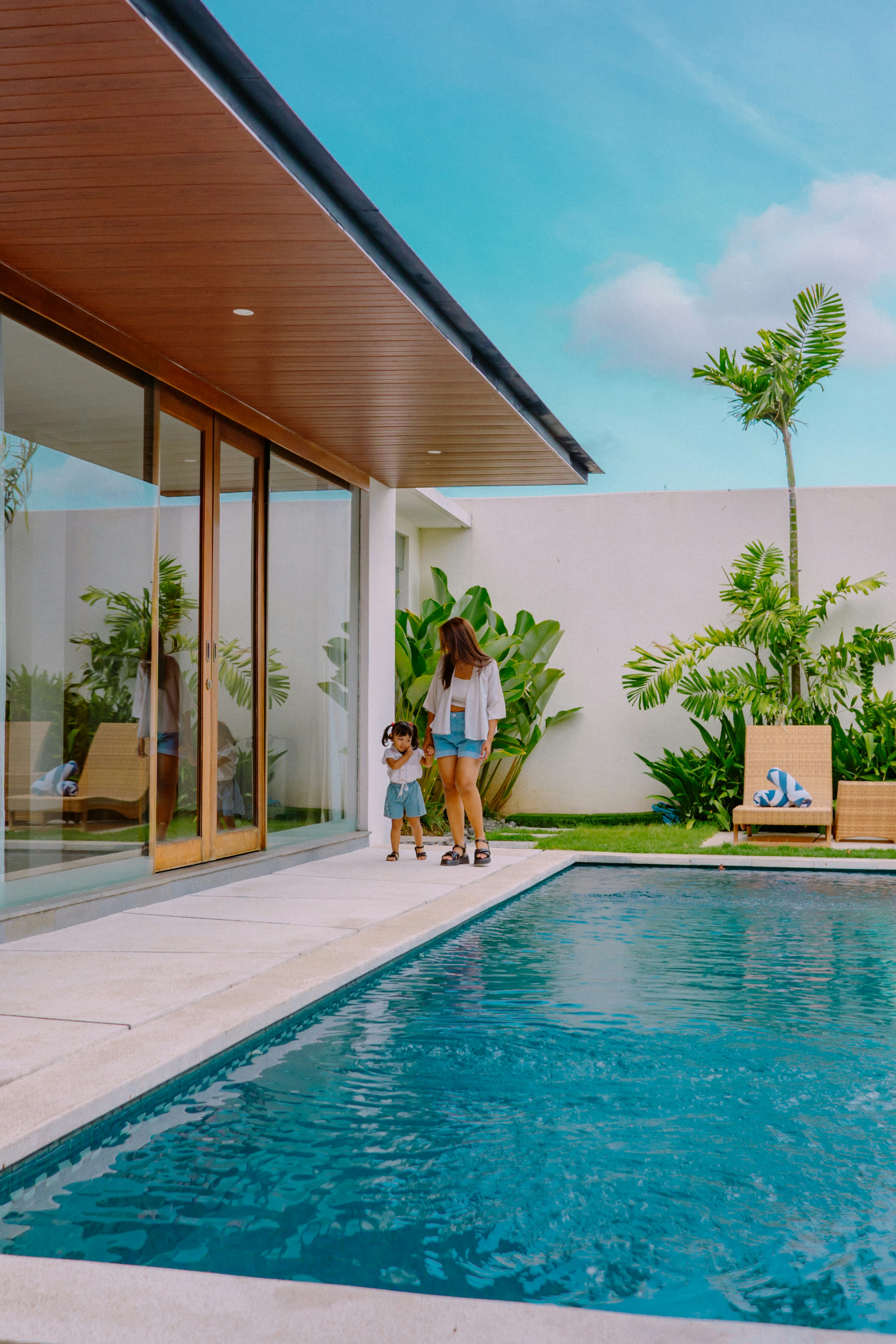A mother and child walk along the edge of a private swimming pool in a modern tropical villa. Captured in Bali, Indonesia — this image showcases serene family moments and resort-style living. | Mother and child stand near the pool.