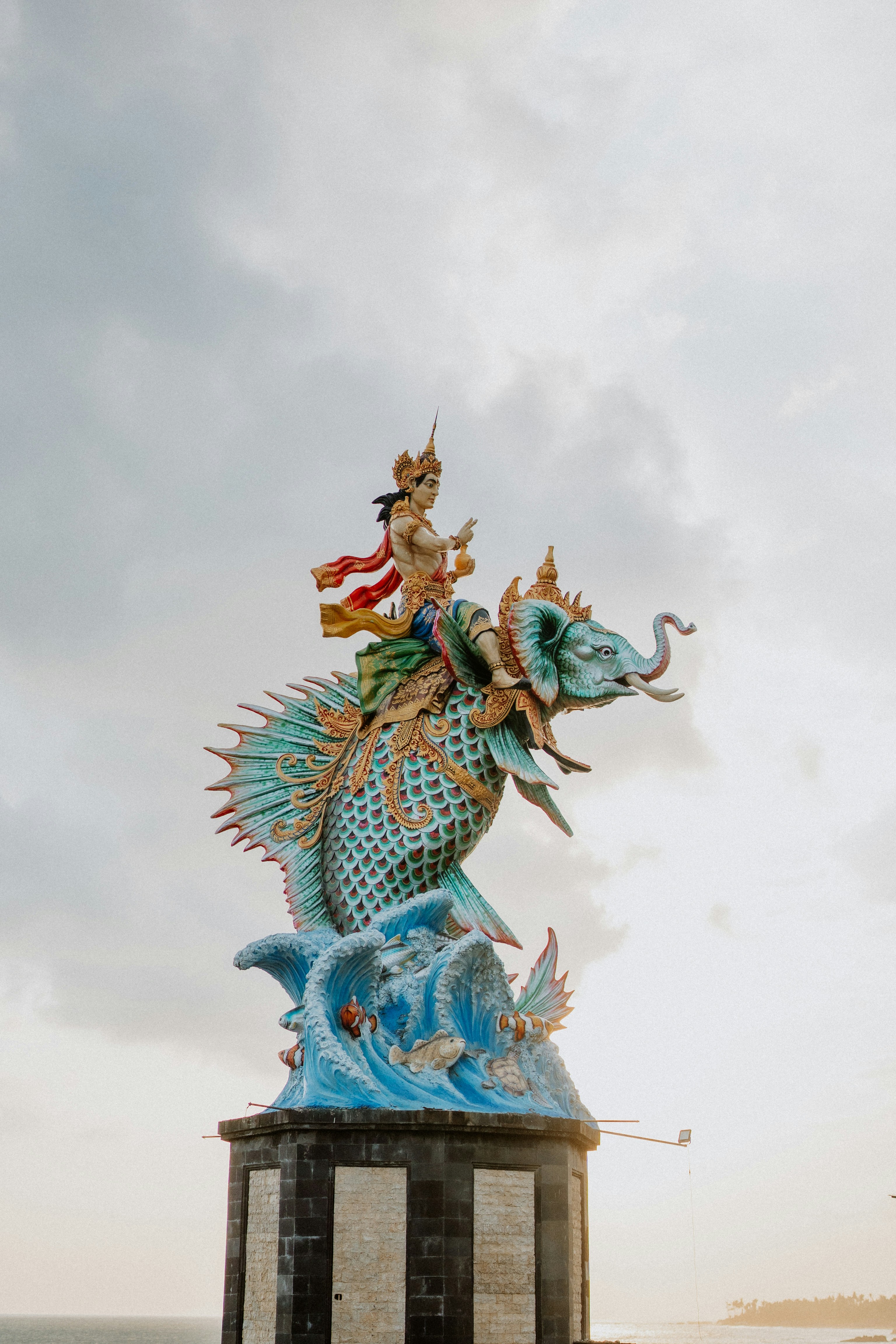 The Gajah Mina statue, a mythical elephant-fish figure from Balinese Hindu mythology, standing tall against the cloudy sky at Pererenan Beach, Bali. A symbol of cultural and spiritual heritage. | A colorful statue of a mythical creature.