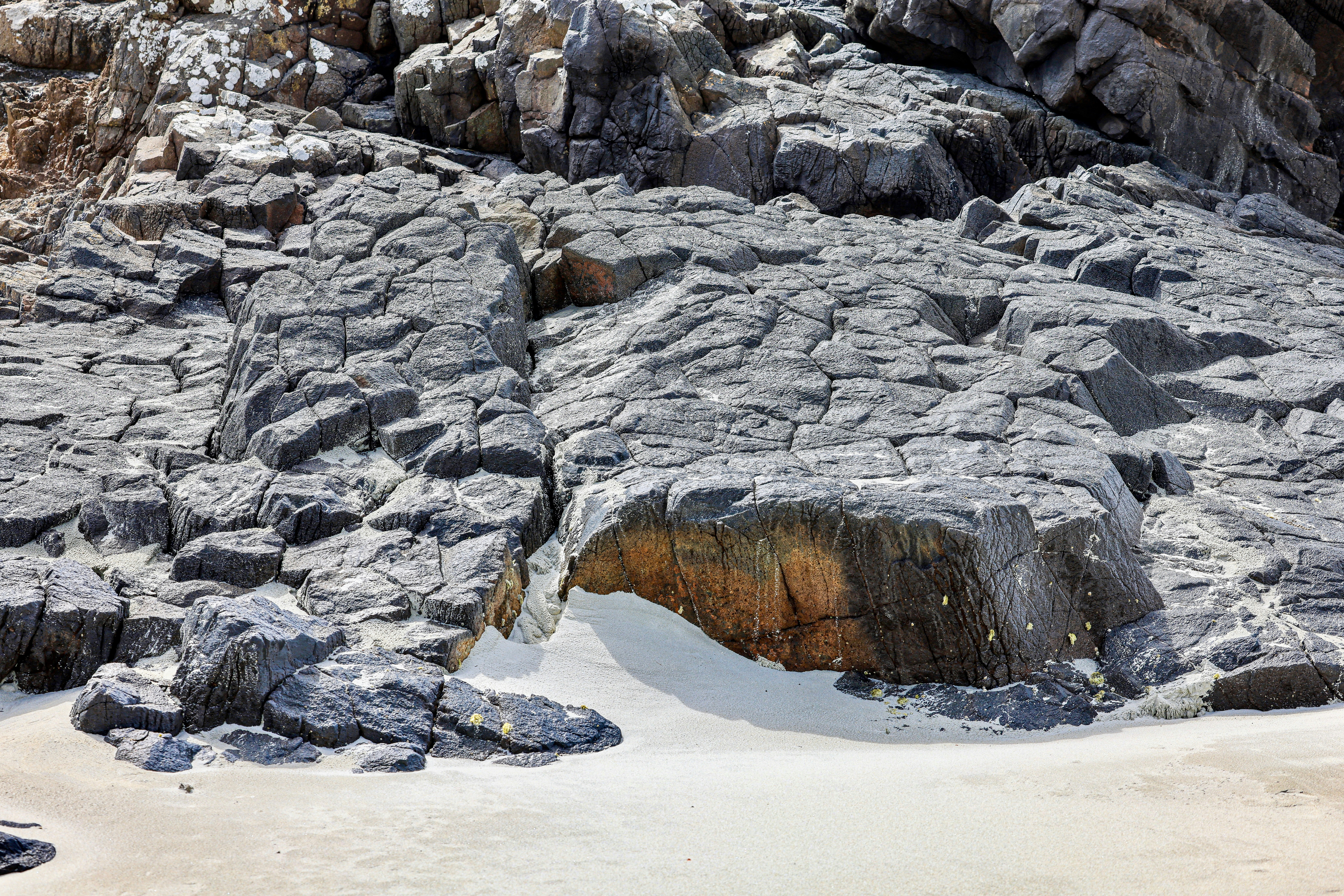 Rocky cliff overhangs a sandy beach. photo – Free Scenery Image on Unsplash