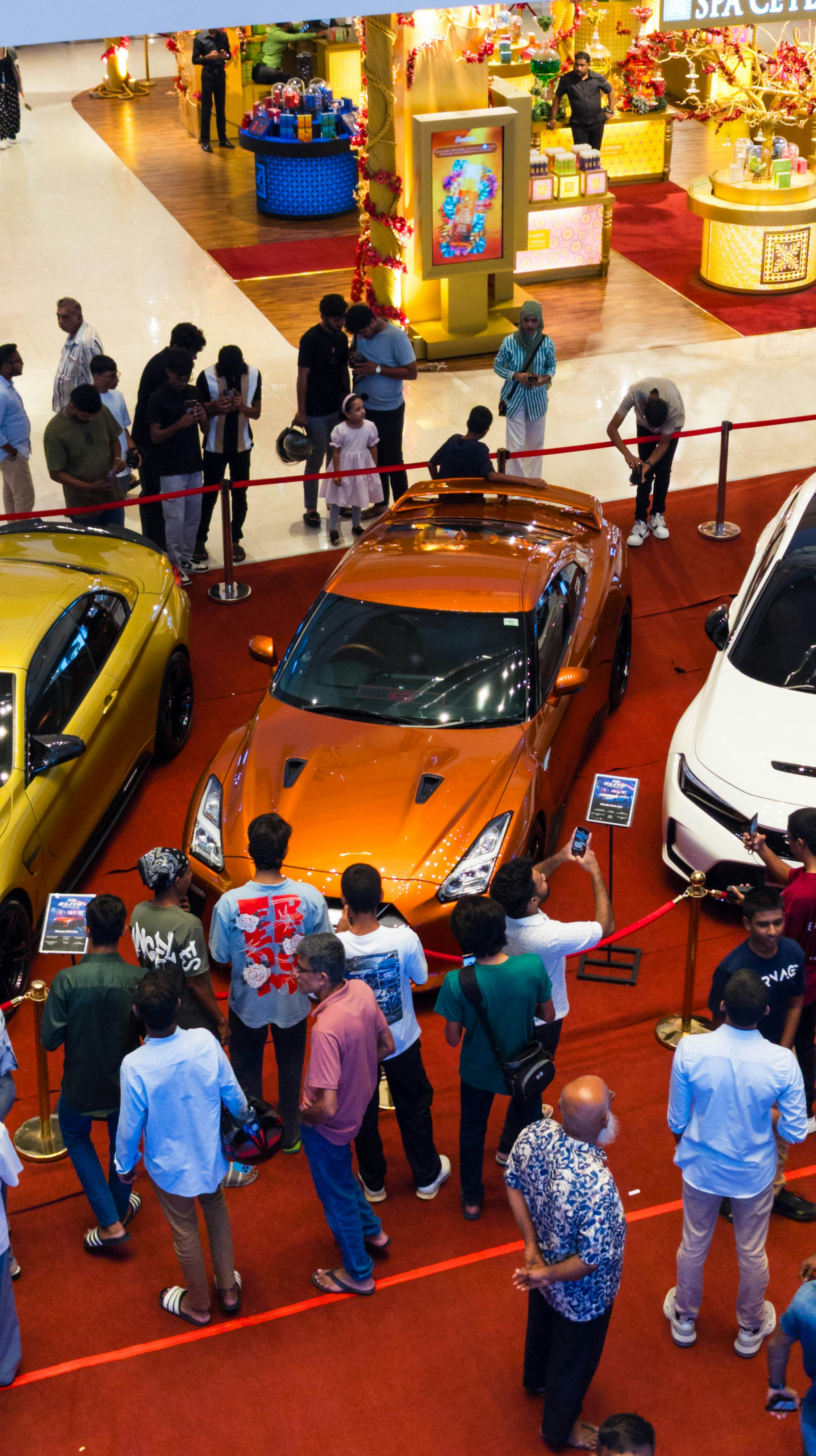 Orange Centerpiece: A Buzzing Crowd Around a Sleek Showroom Gem