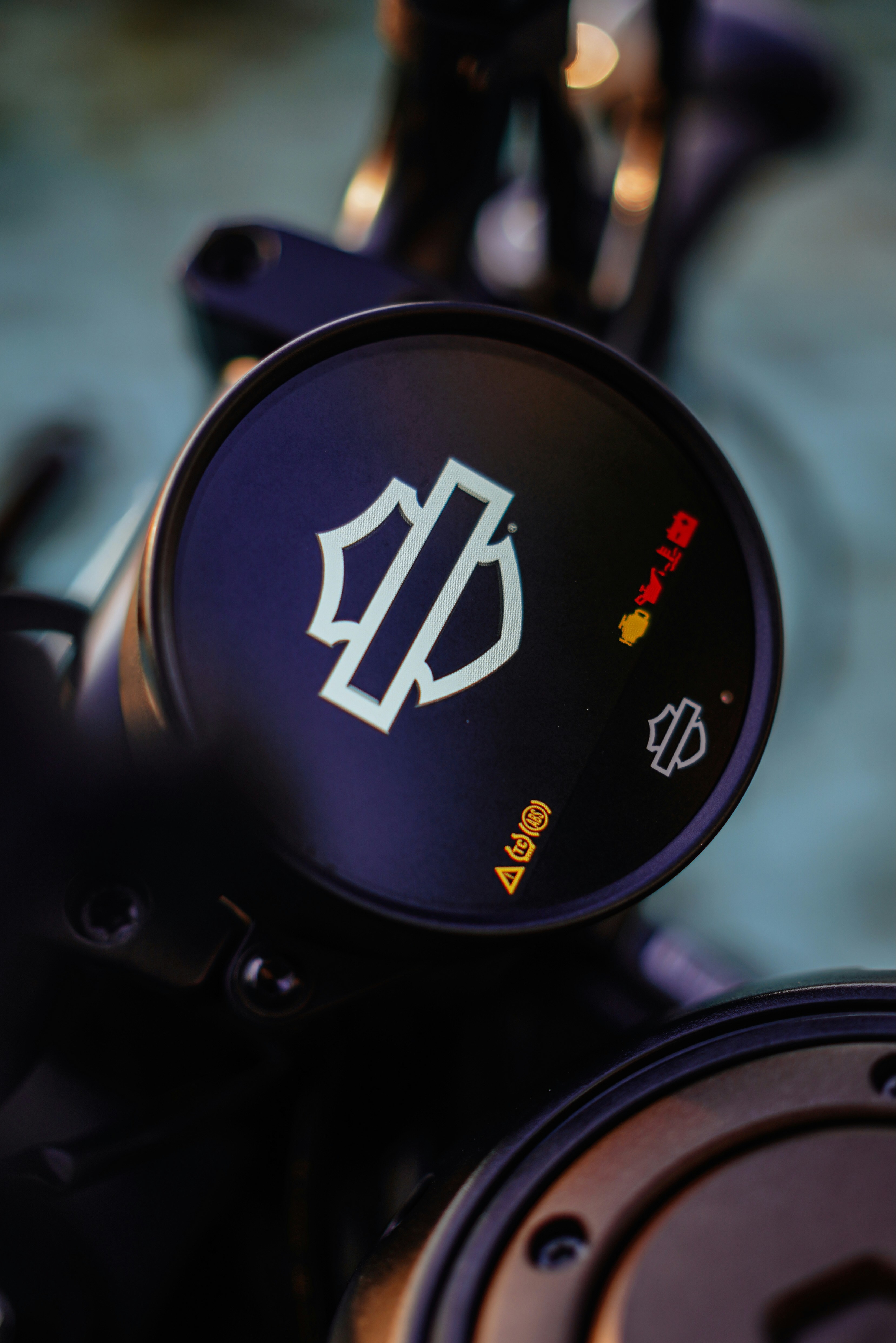 Close-up of a motorcycle dashboard gauge displaying vital information, featuring a prominent logo and warning indicators.