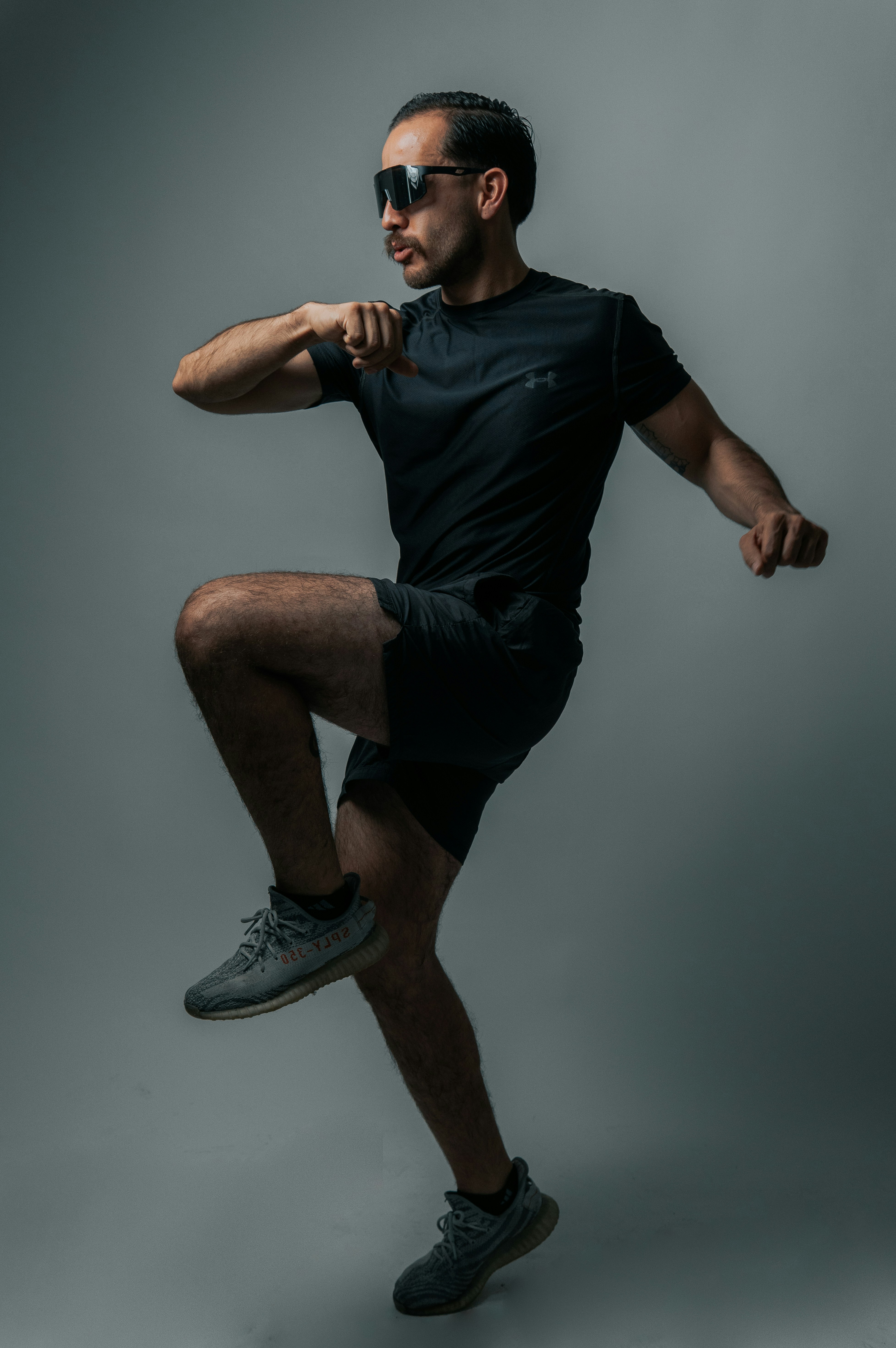 Retrato dramático de hombre con gafas deportivas oscuras en fondo oscuro | Man in sunglasses demonstrates a workout routine.