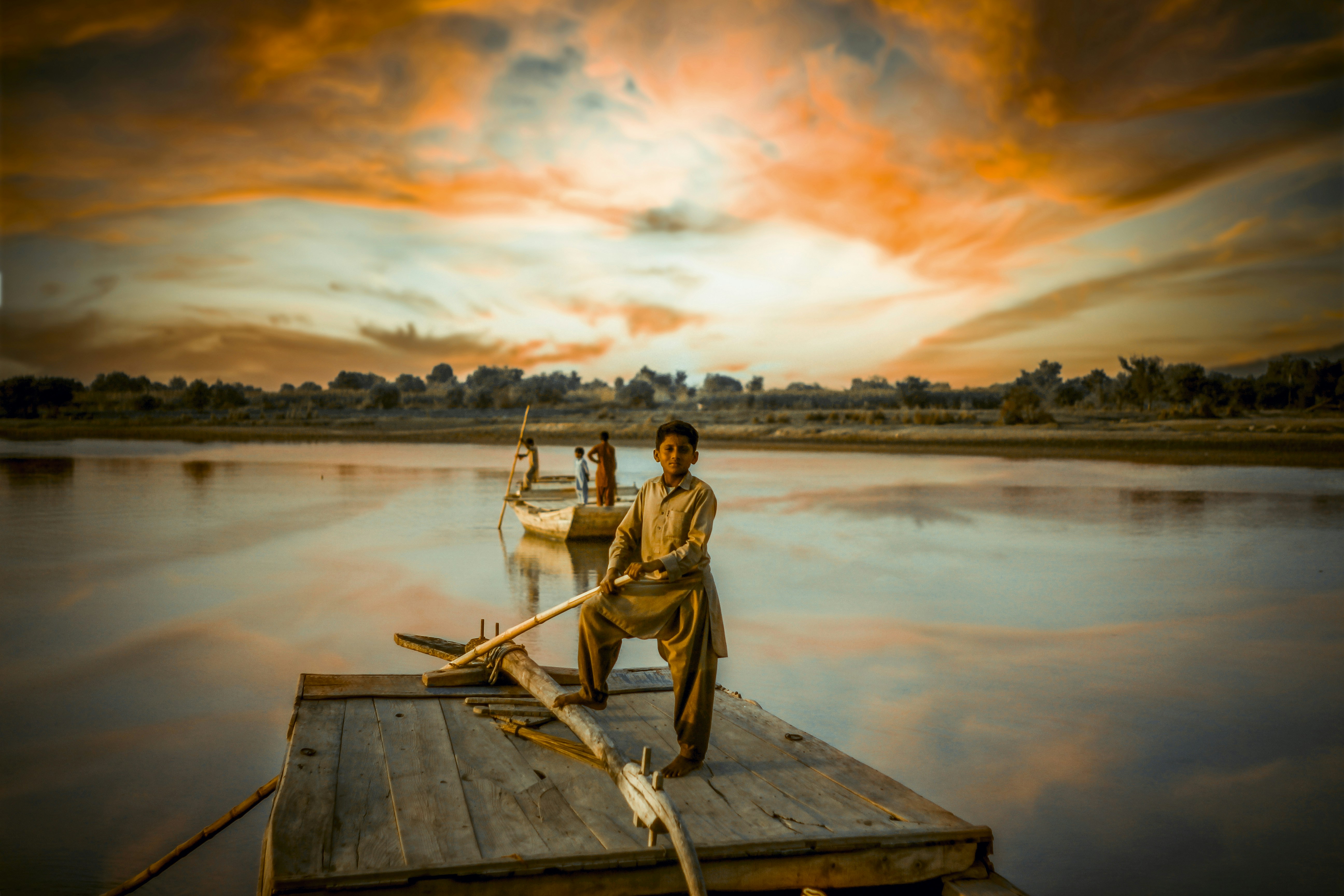 A man rows a boat on a river at sunset.