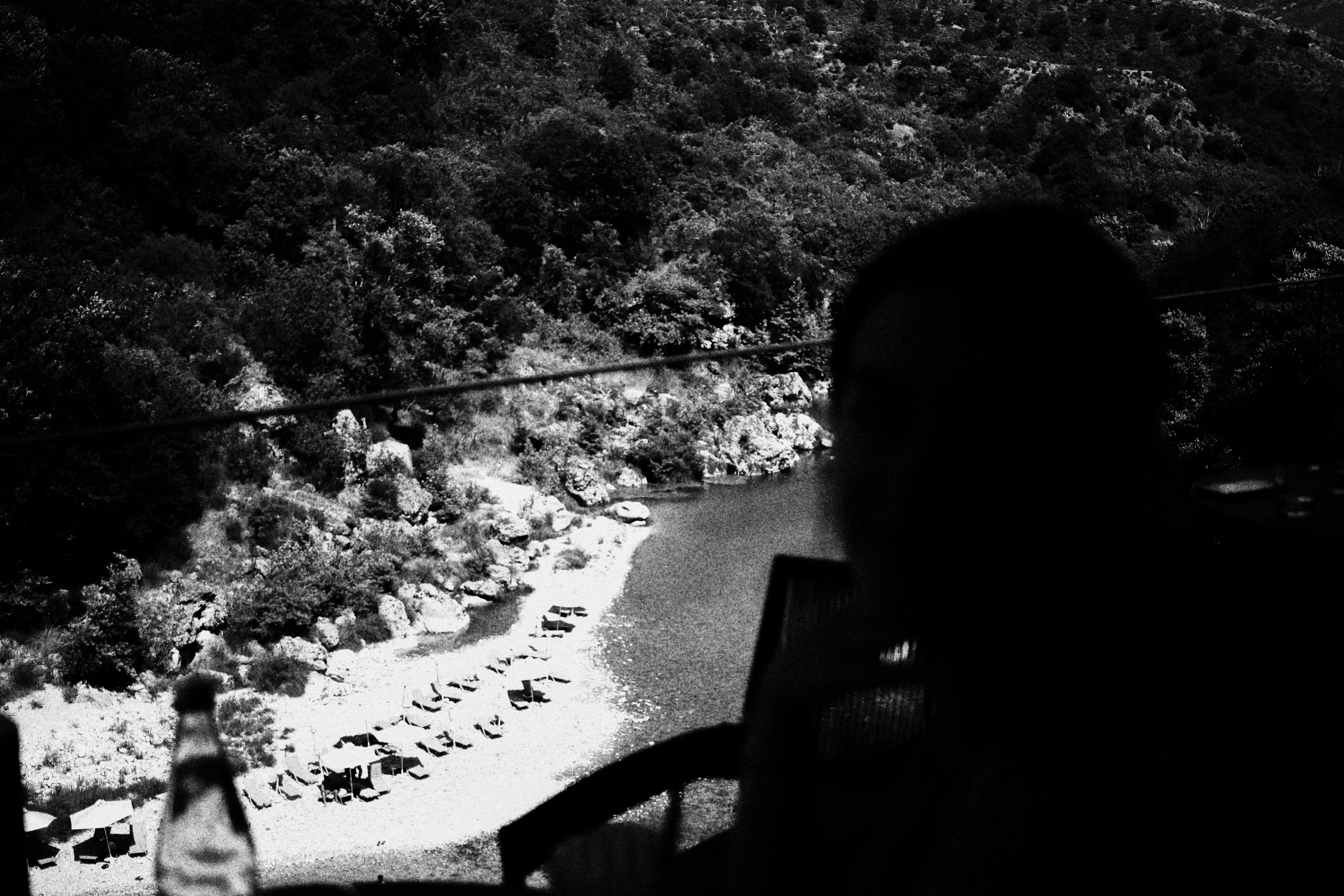 Silhouette of a person framed against a serene river landscape, highlighting the contrast between human presence and the untouched beauty of nature.