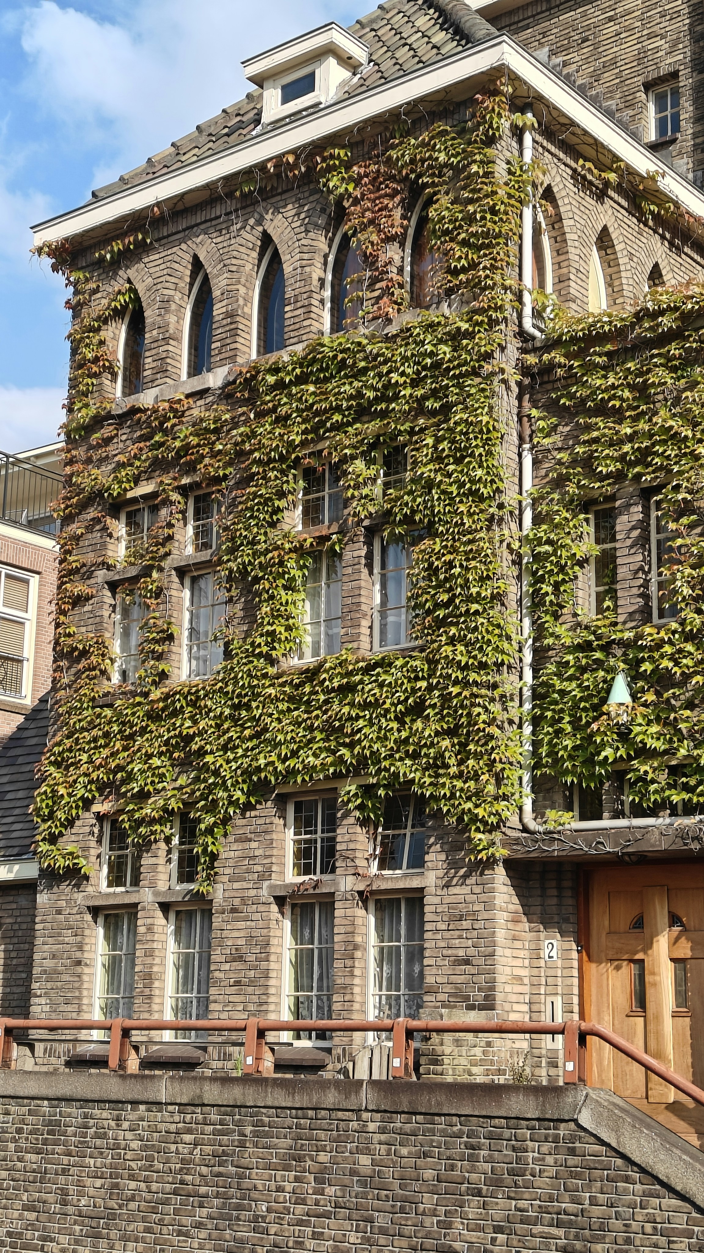 Urban building with nature: ivy | A brick building covered in green vines.