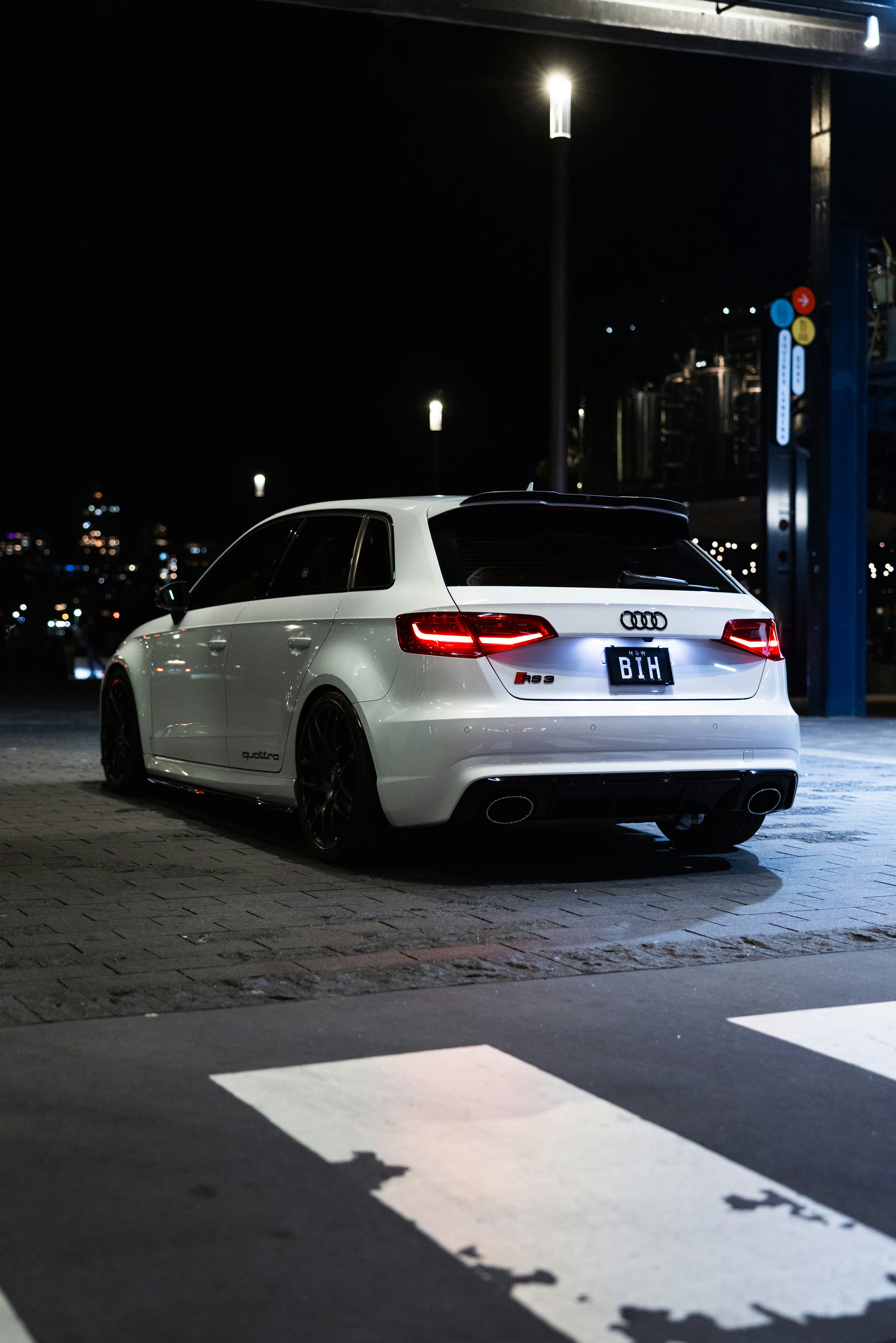 Nocturnal rear-quarter view: white Audi sportback under urban glow