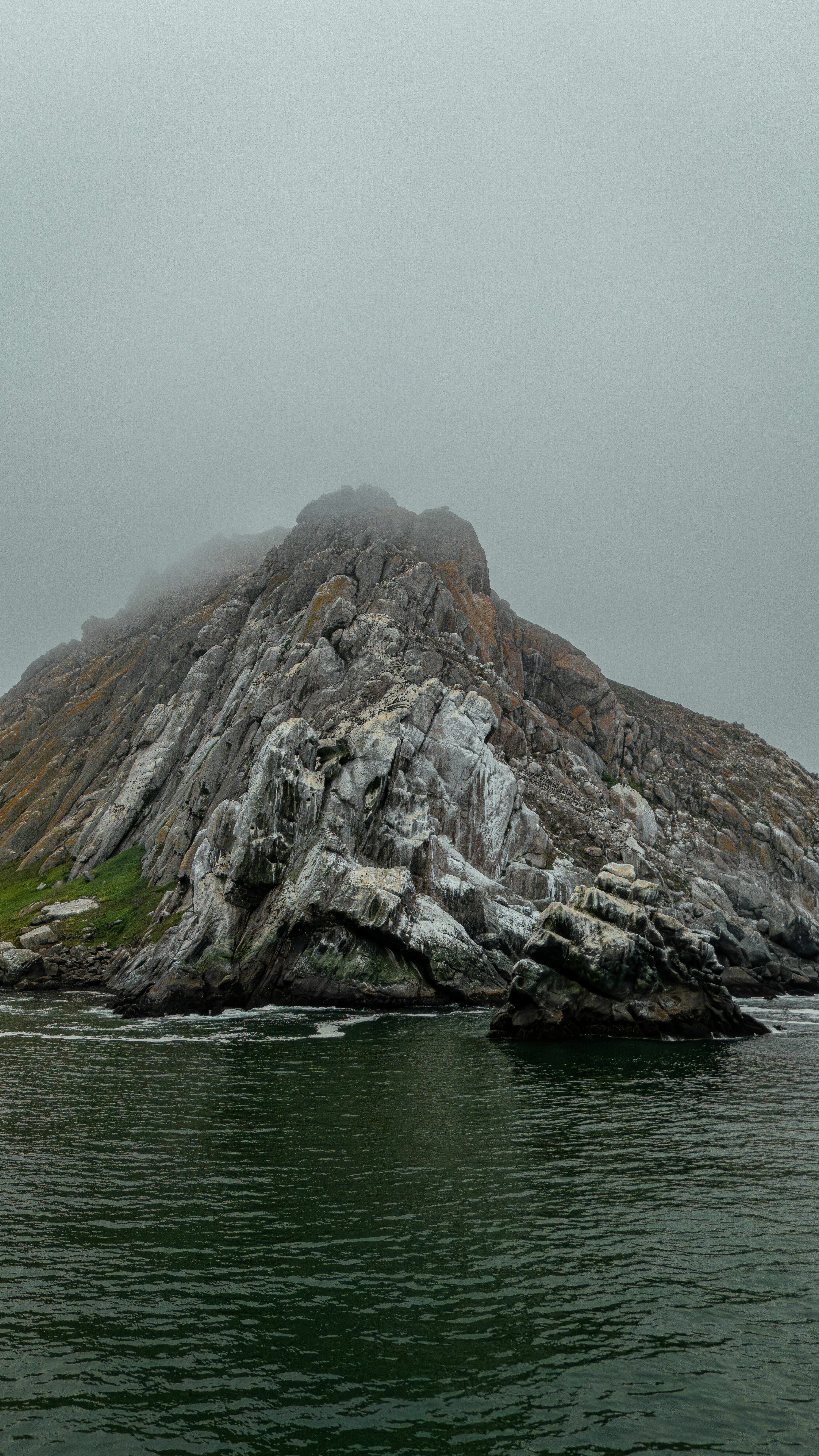 Mist-Guarded Monolith: Granite Peak Rising from Quiet Seas
