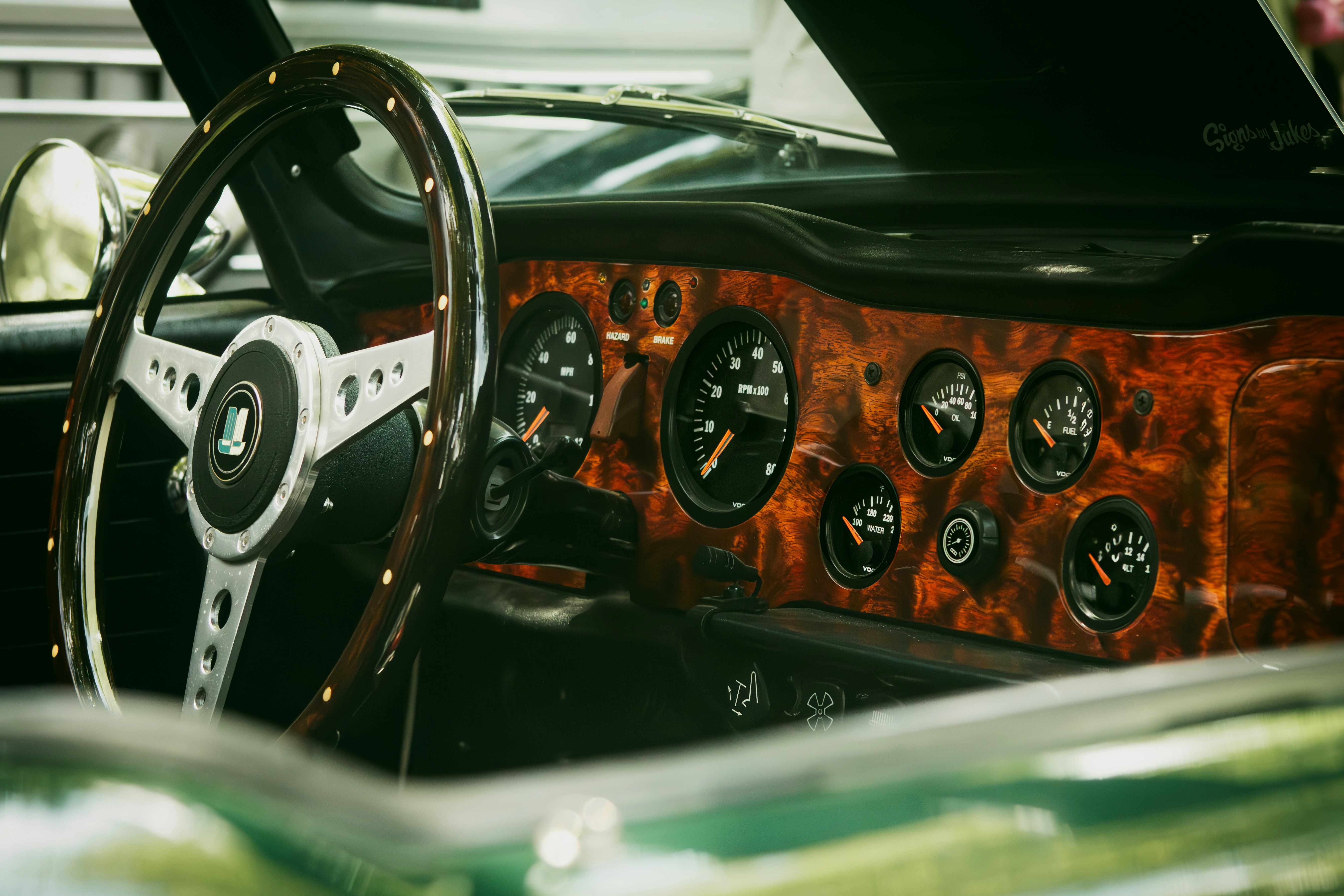Classic car's wooden dashboard and steering wheel are visible.
