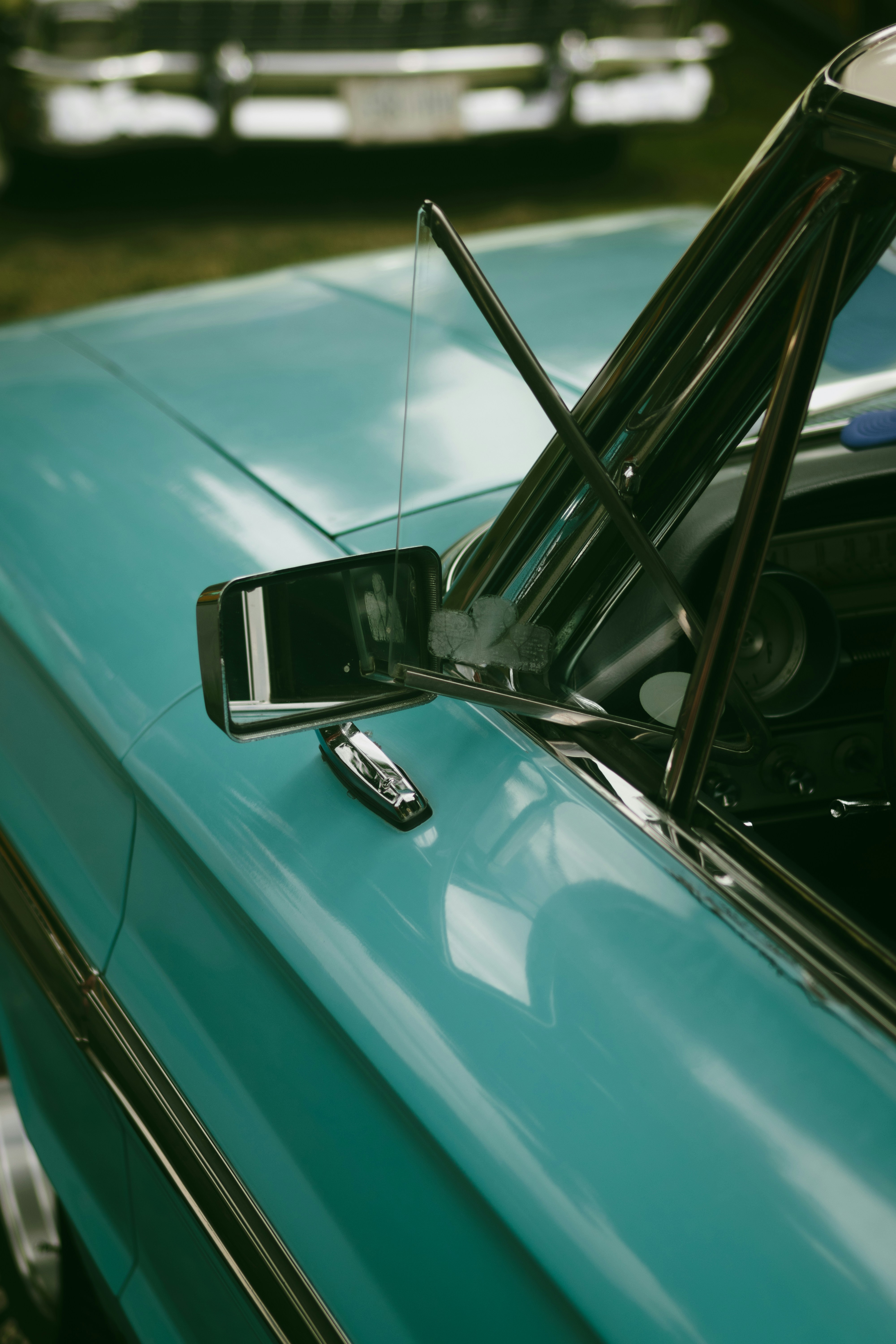 A turquoise vintage car's side mirror.