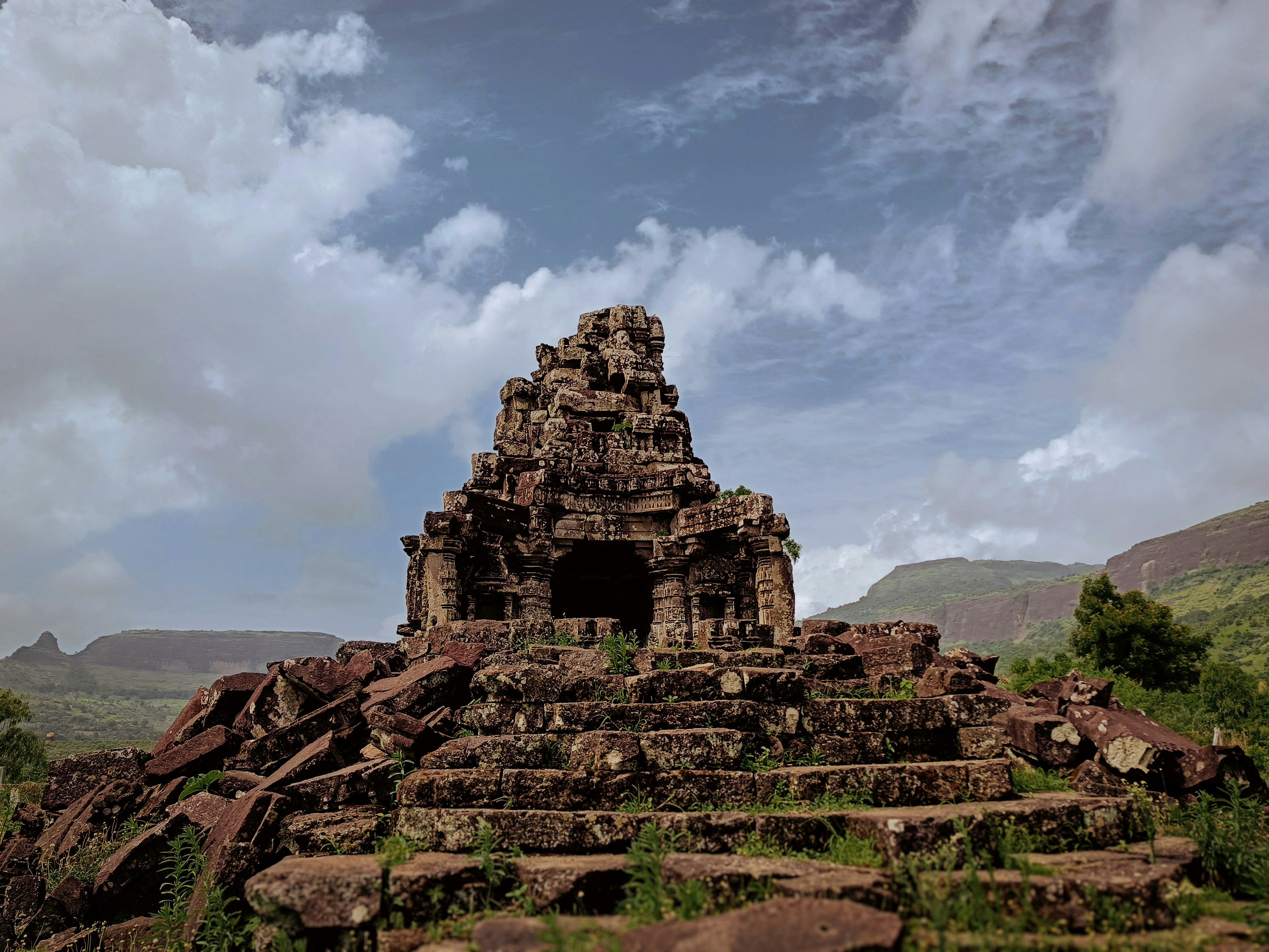 Ruins of an ancient hindu temple. | Ancient temple ruins stand against a cloudy sky.