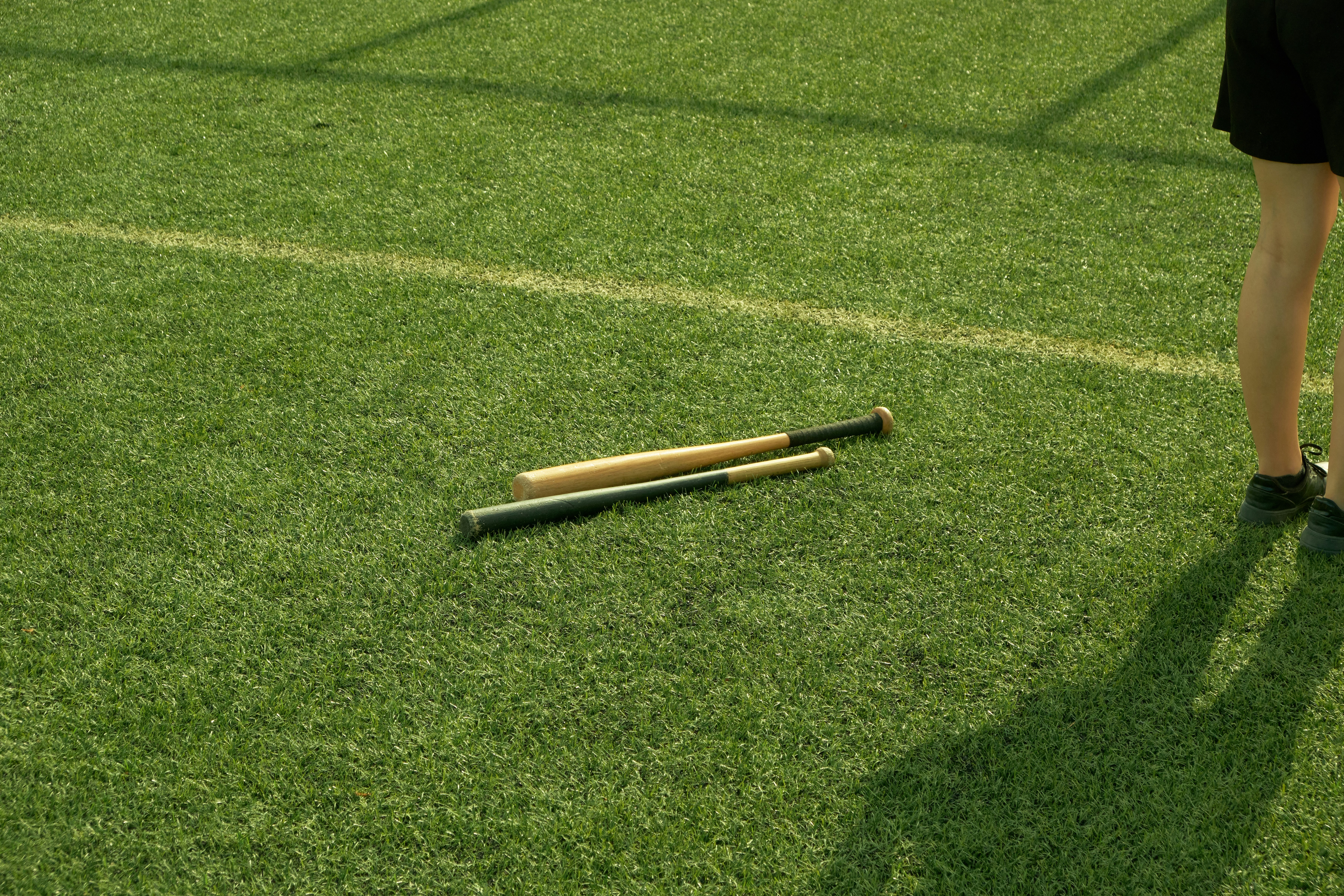 Baseball bats are on a green field.
