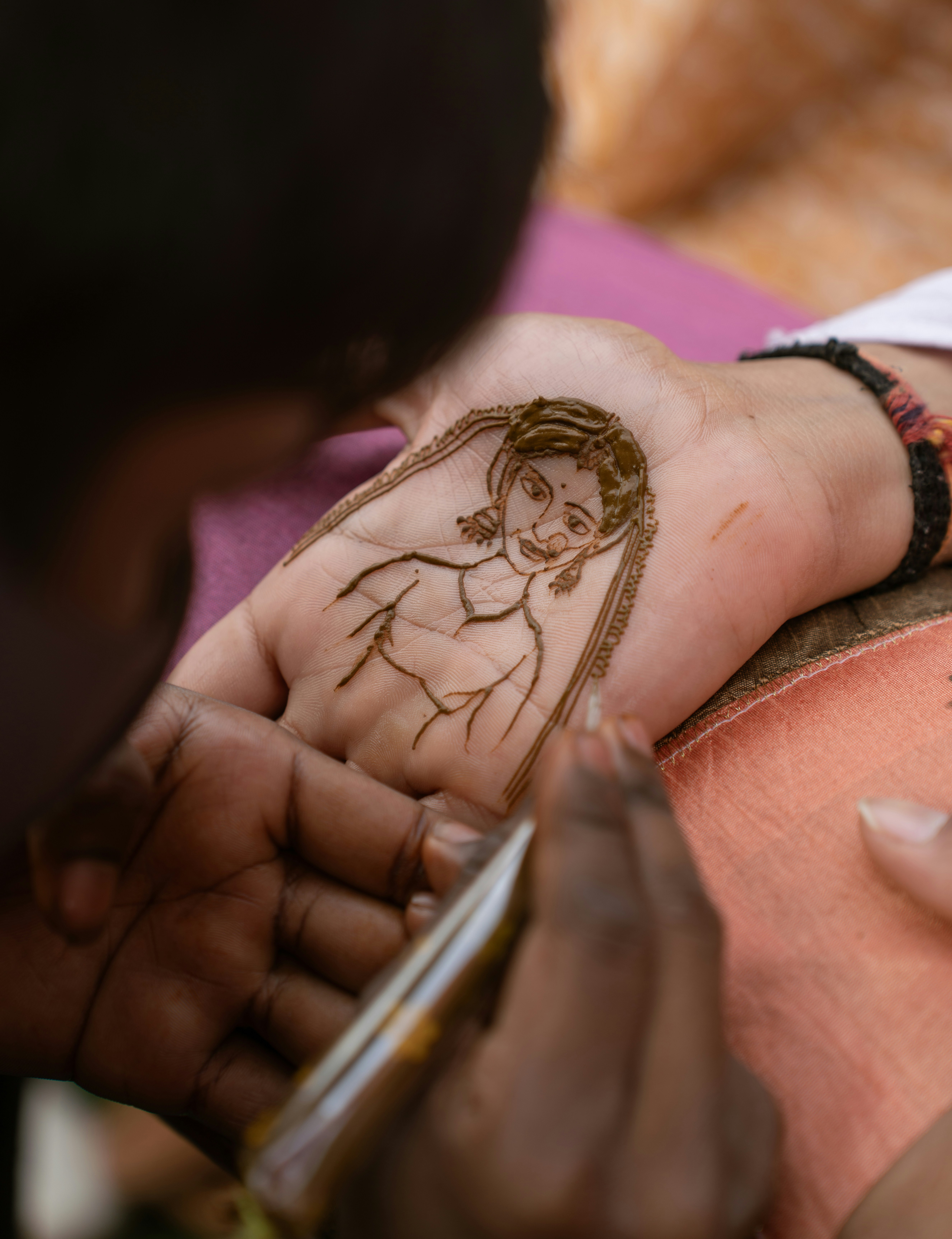 Henna artist creates a portrait on someone's hand.