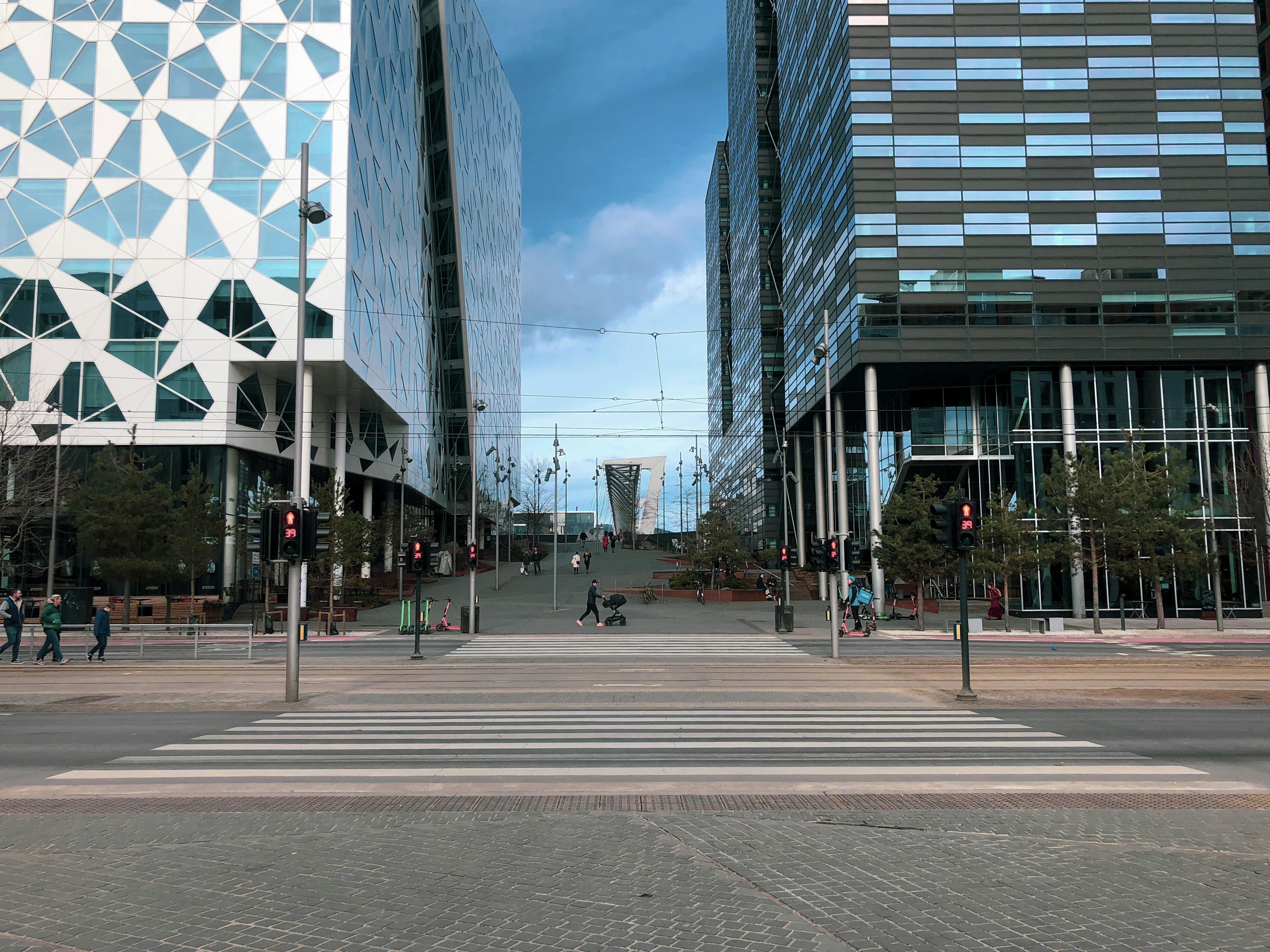 Modern city buildings line a pedestrian walkway.