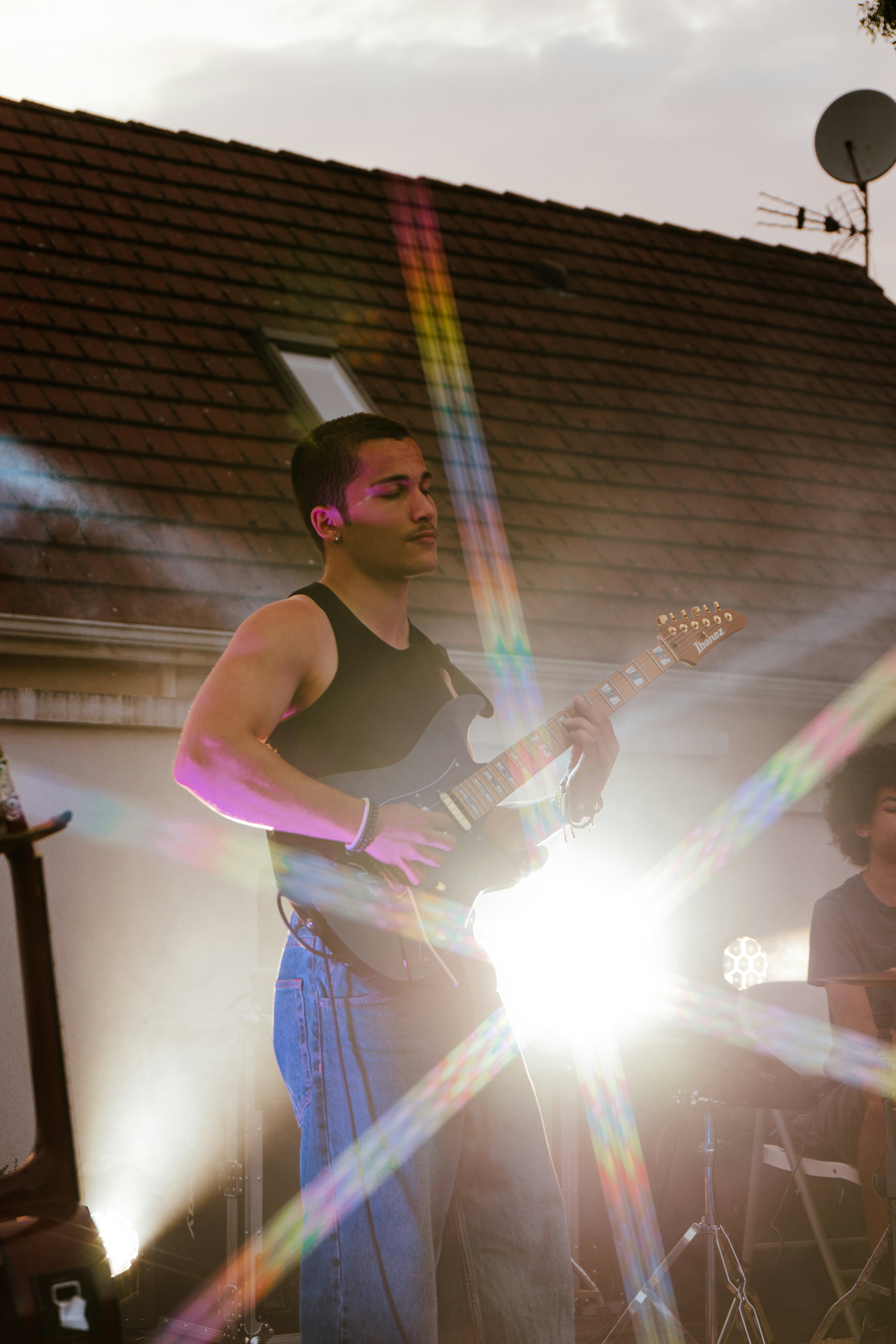Guitarist plays under stage lights outside.