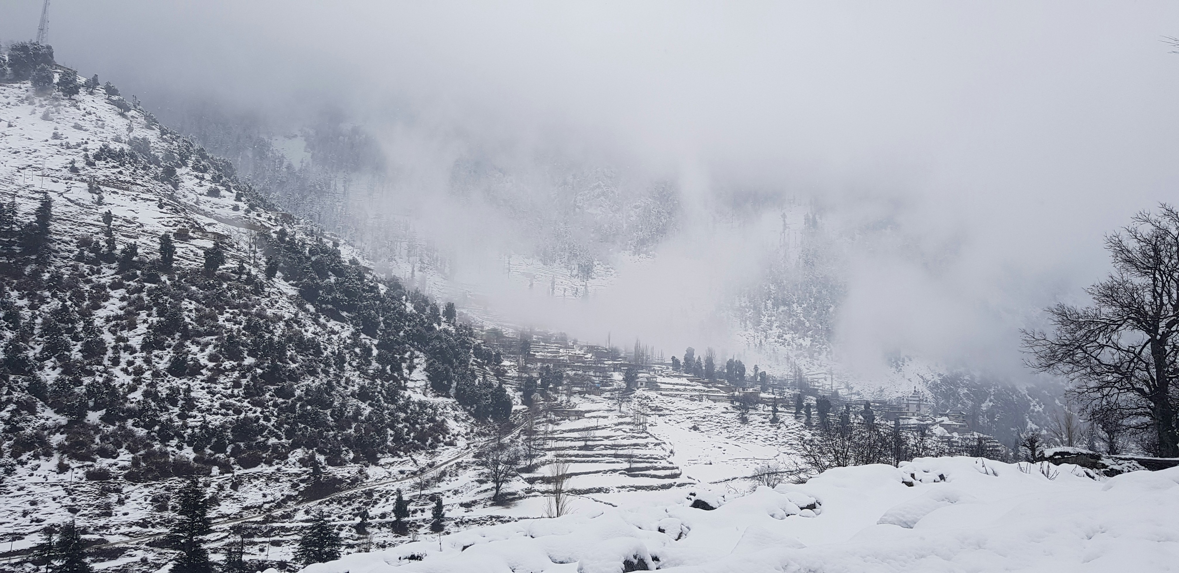 Snow-covered mountain scene with foggy sky.