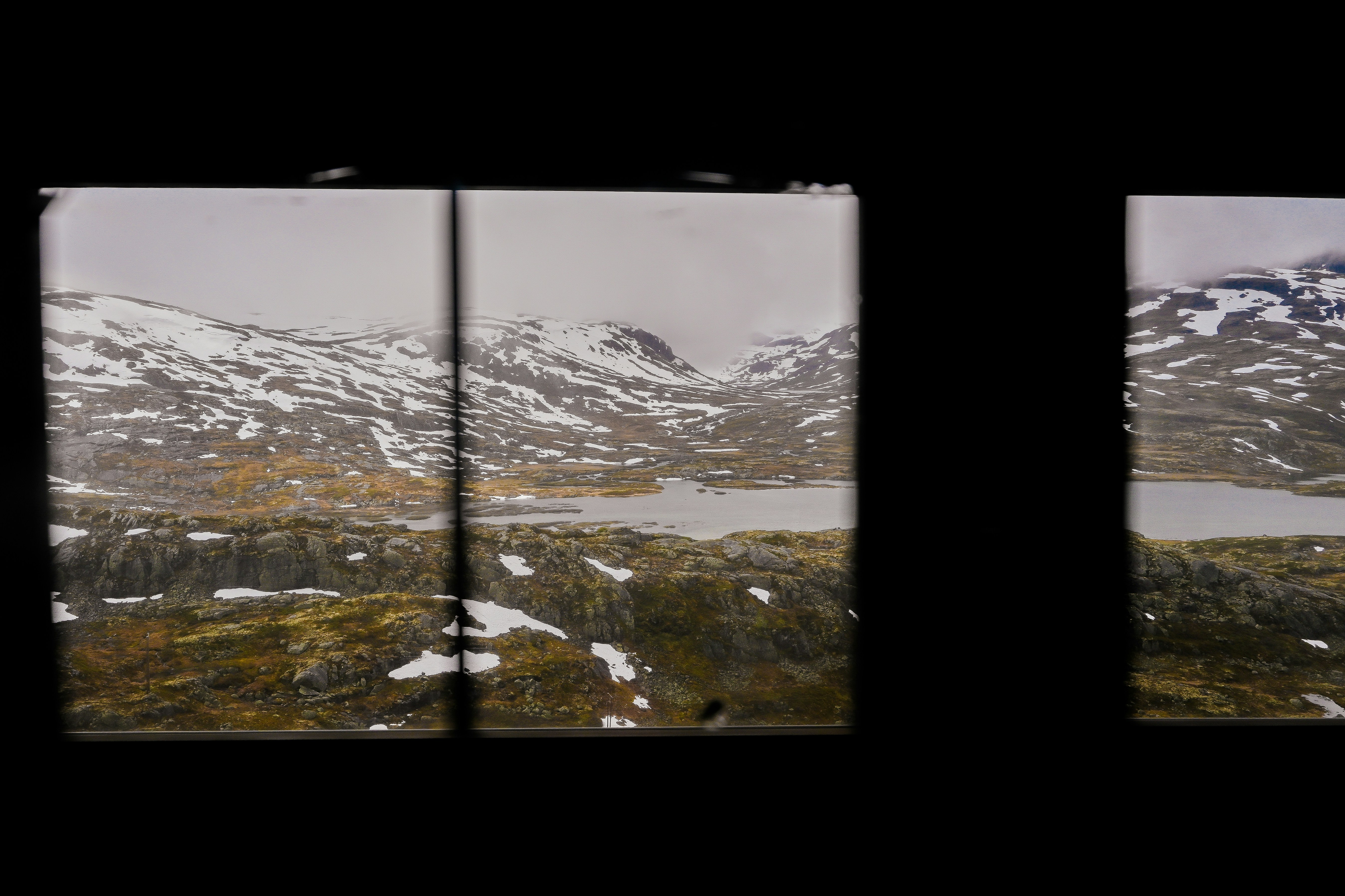 Snow-capped mountains and a lake framed by windows.