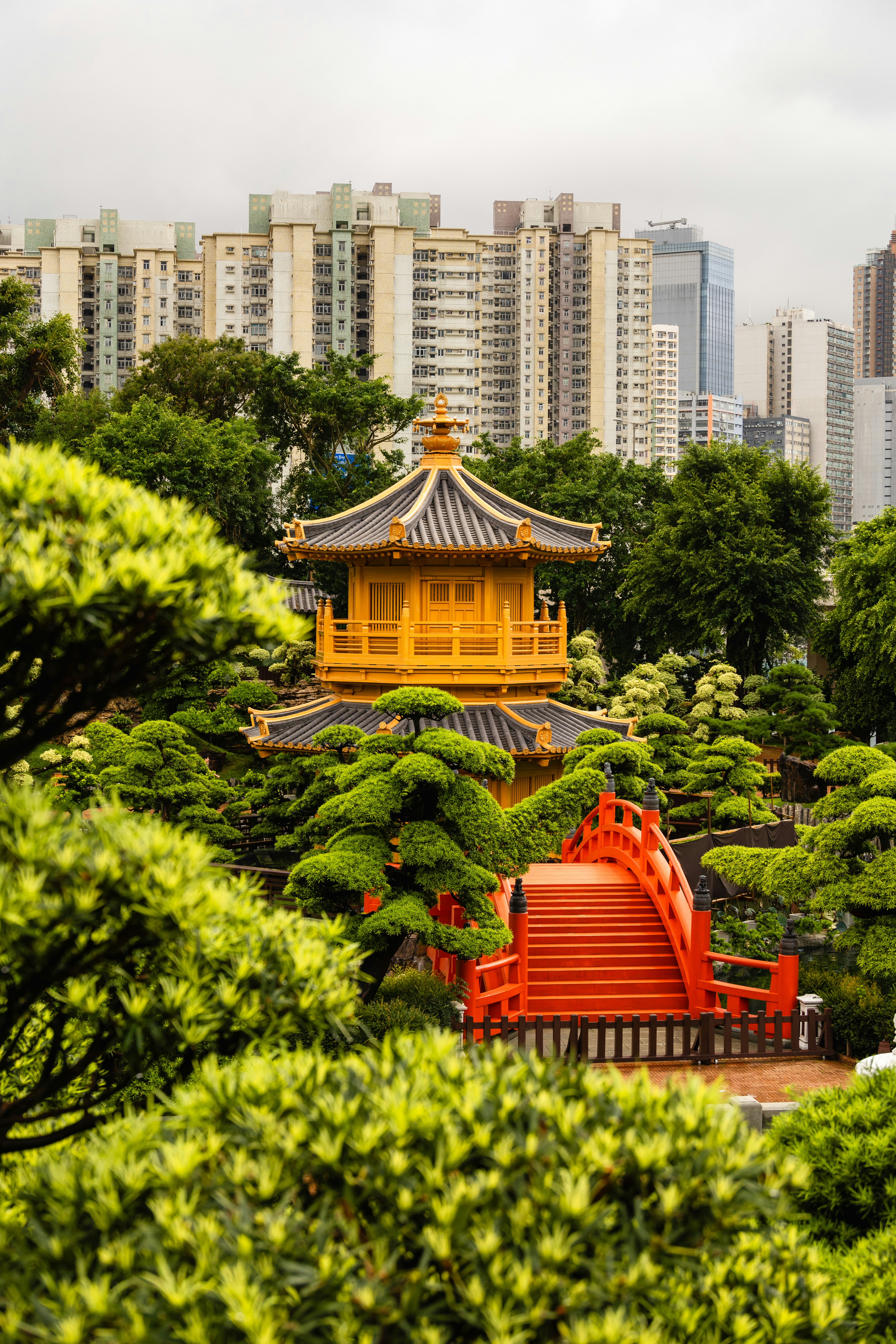 Golden pavilion and red bridge in a lush garden.
