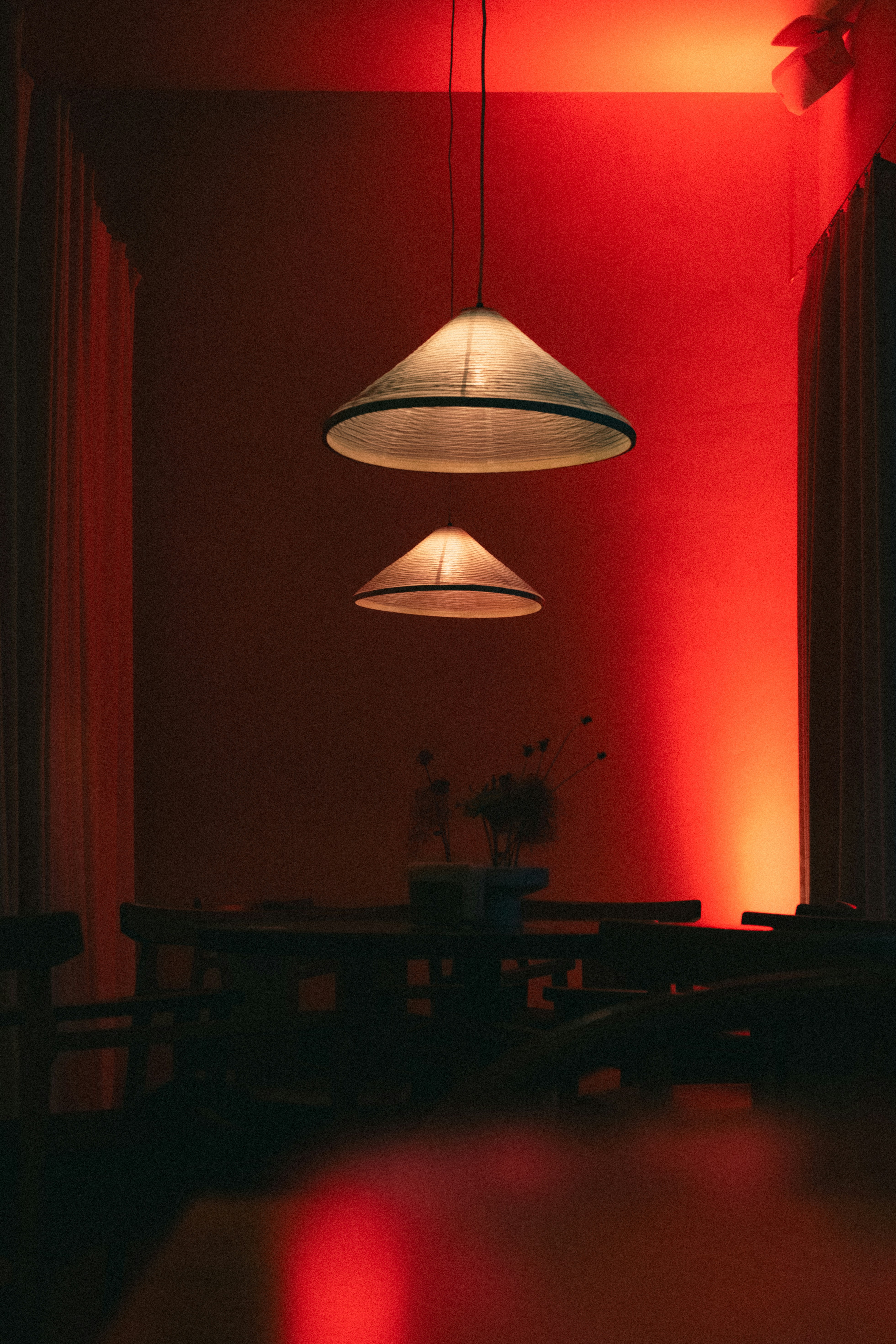 Two lamps hang in a red-lit room.