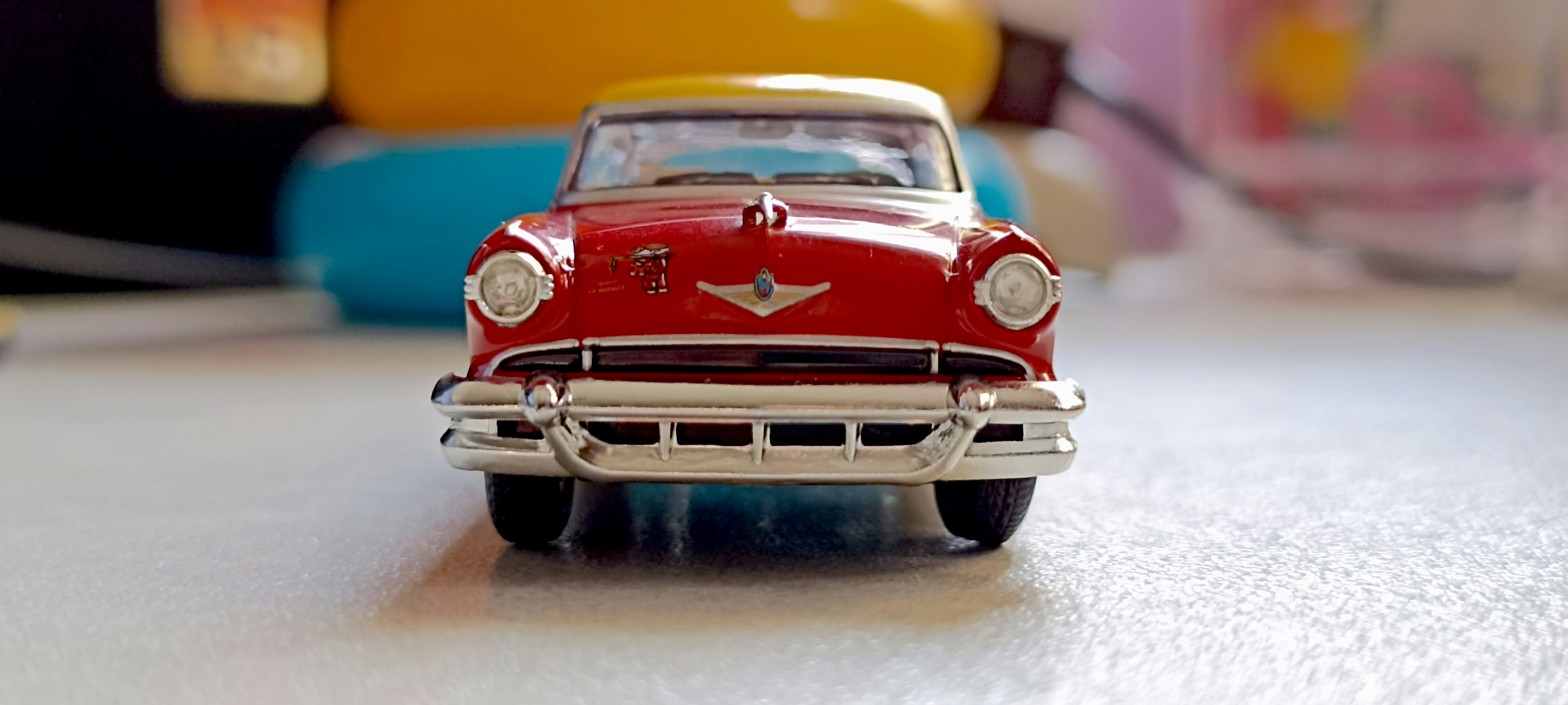 Crimson Classic: A Tiny 1950s Car Anchored on a Sparkling Desk