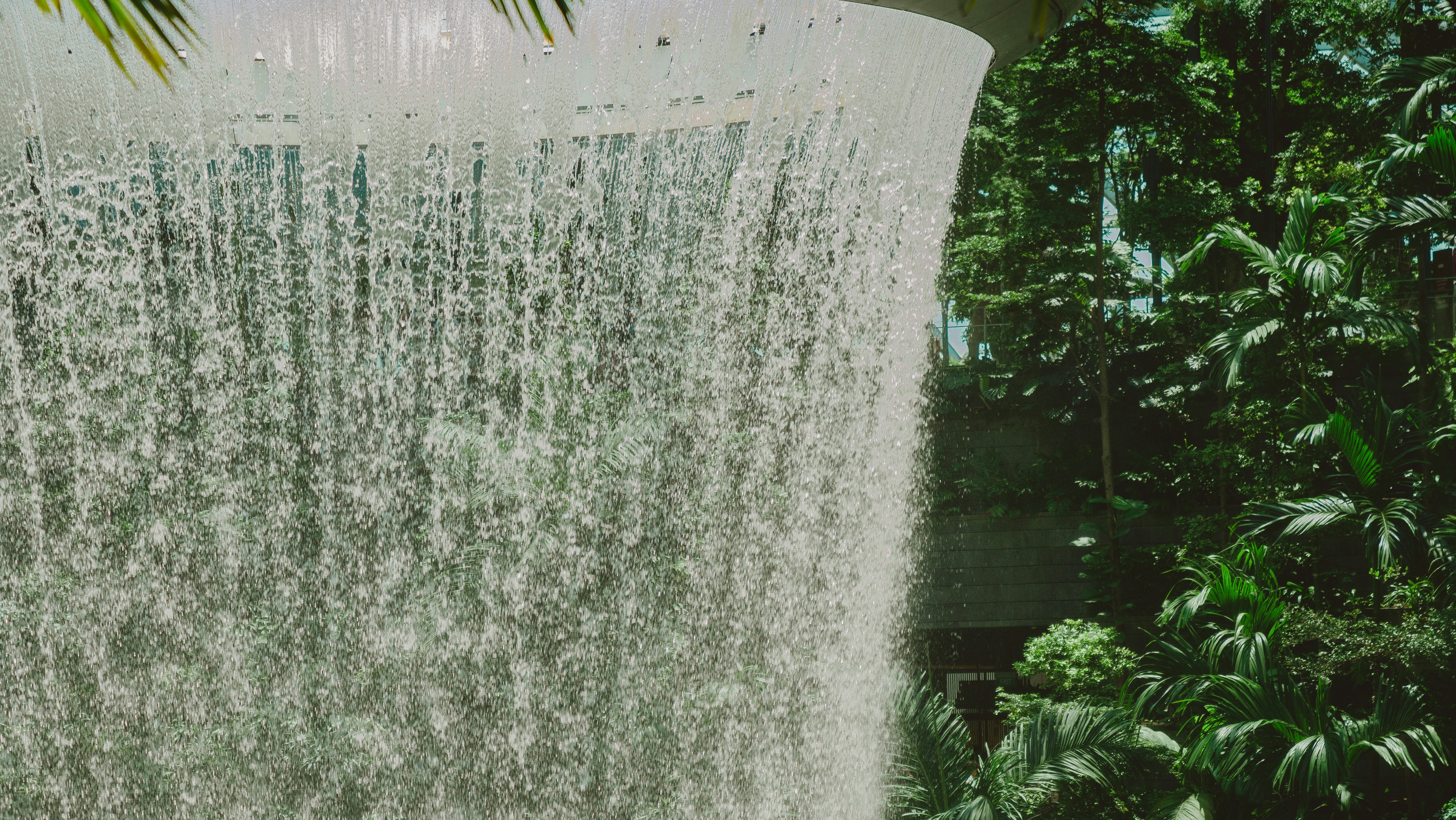 A cascading waterfall surrounded by lush greenery, creating a serene atmosphere in a tropical setting.