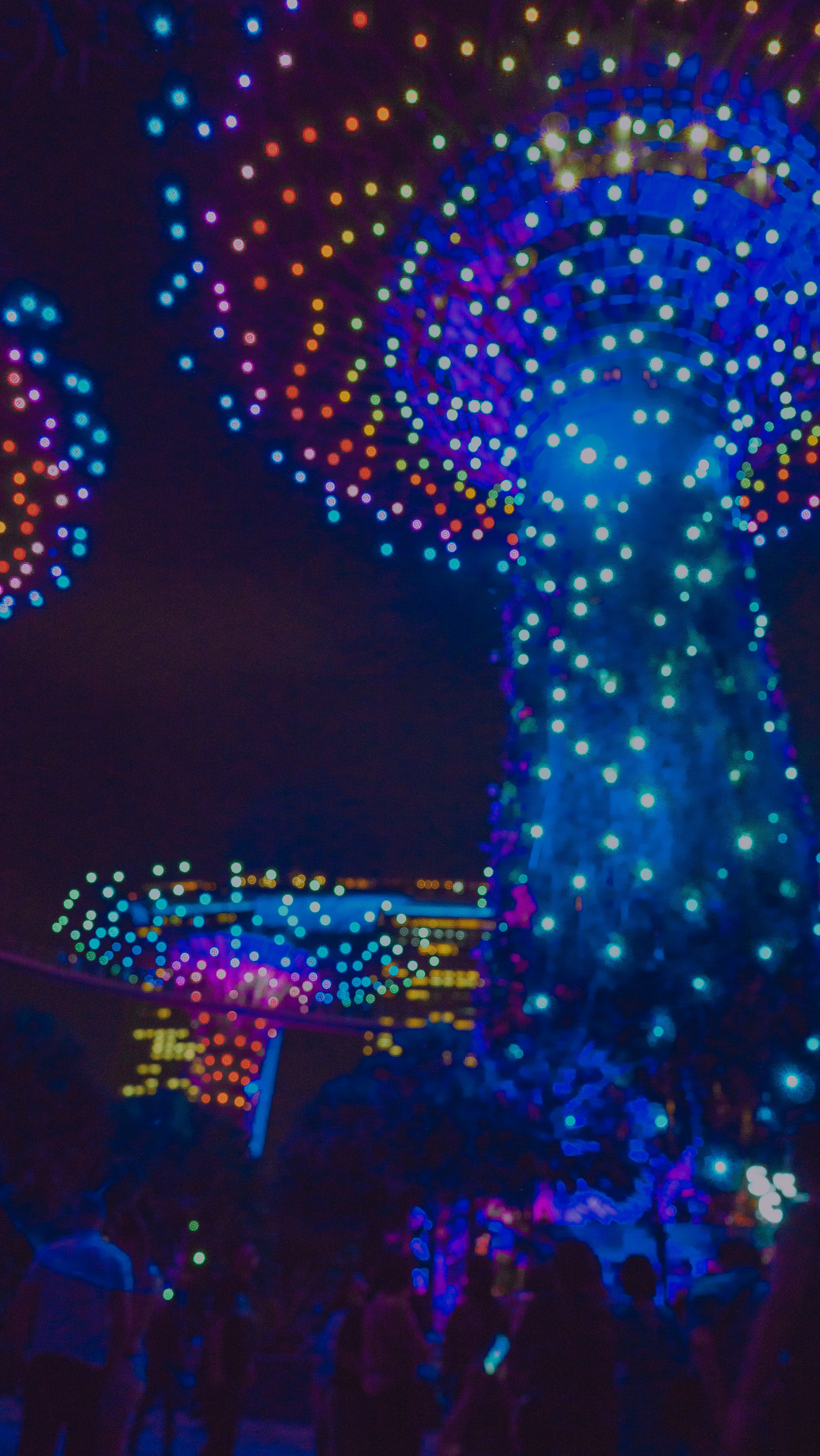 Colorful lights illuminate futuristic-looking structures at night.