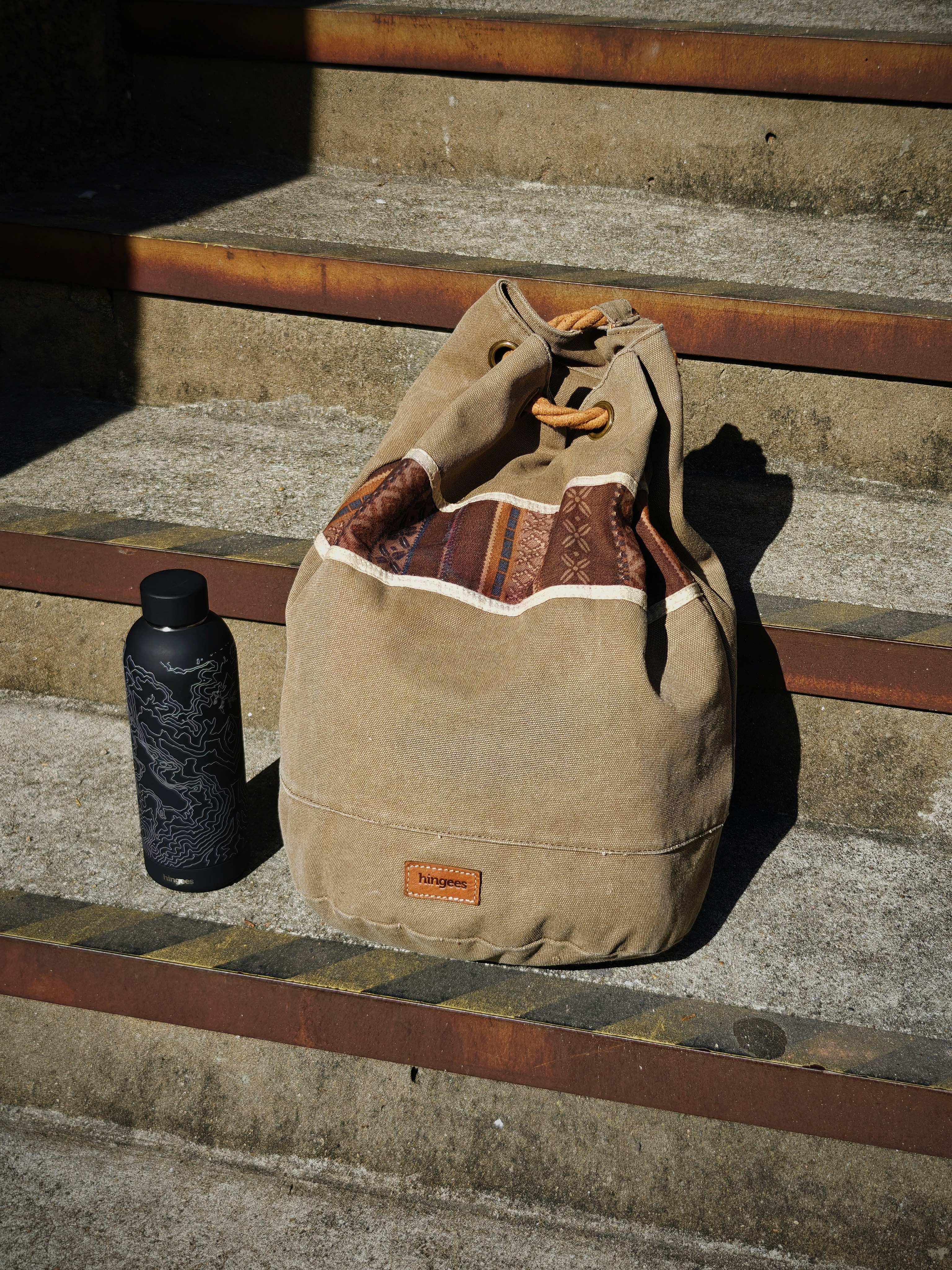 A bag and water bottle on outdoor stairs.