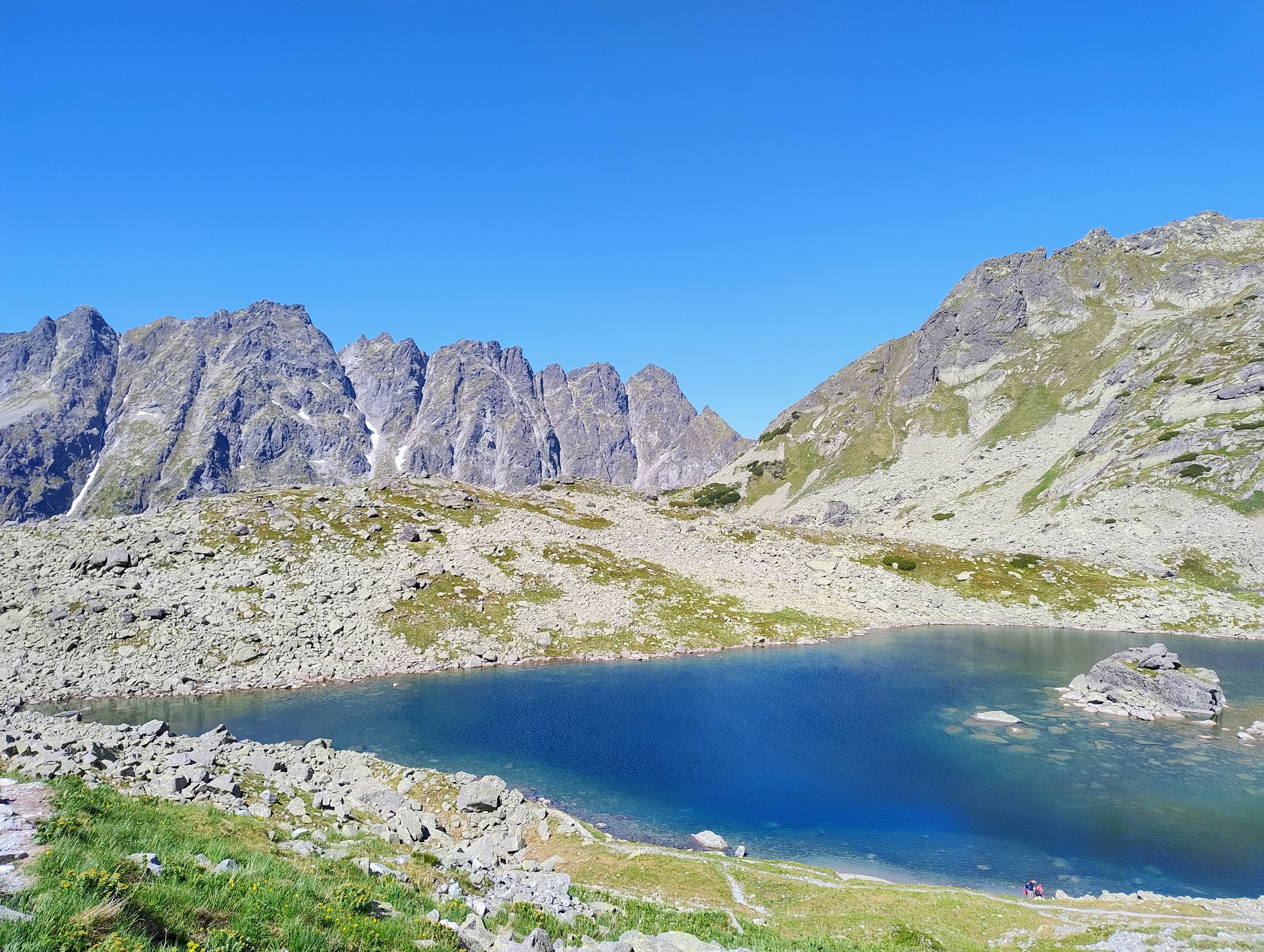Crystal-clear lake nestled between rugged mountains under a vibrant blue sky.