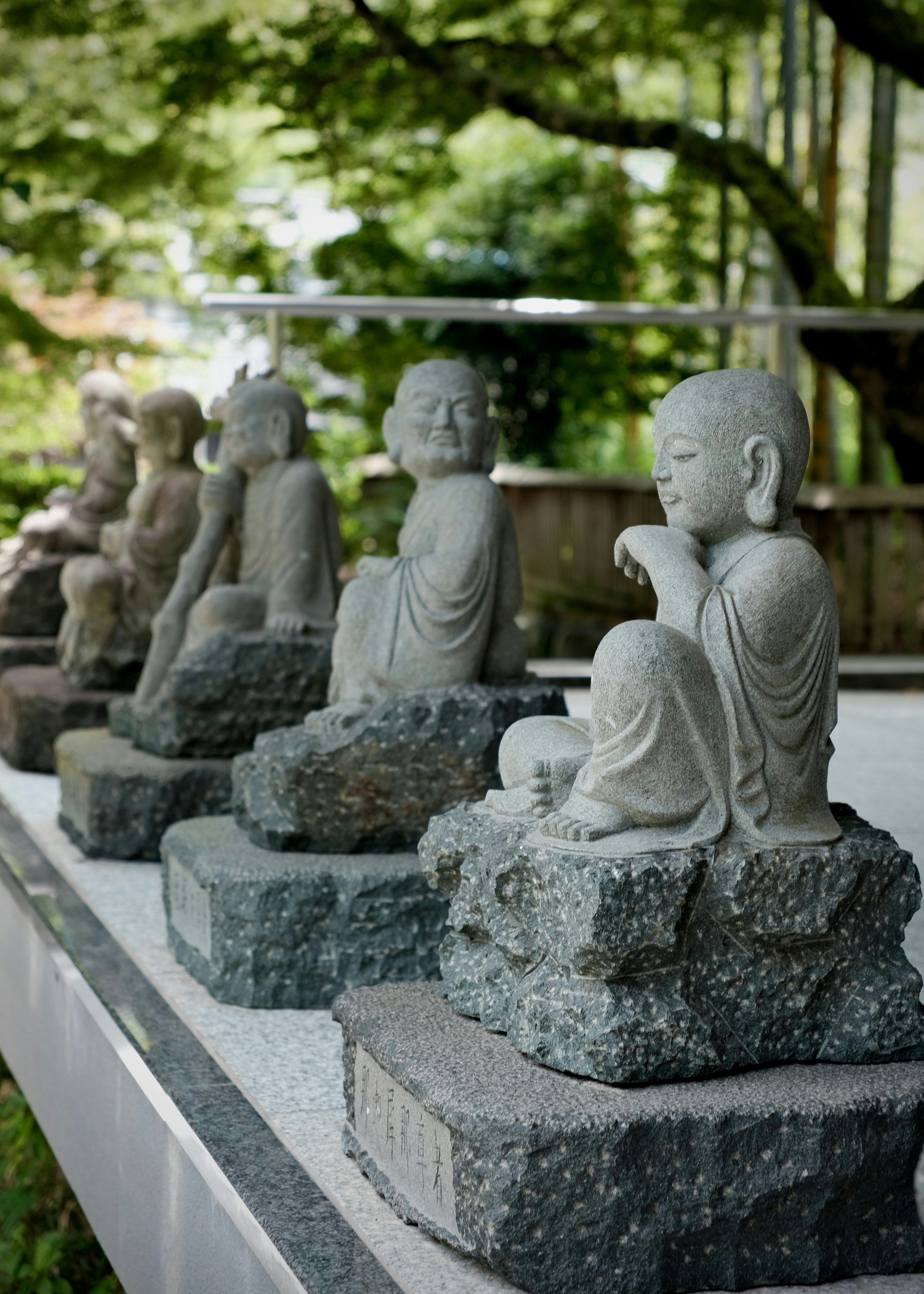 Statues of buddhist monks sit in a row.