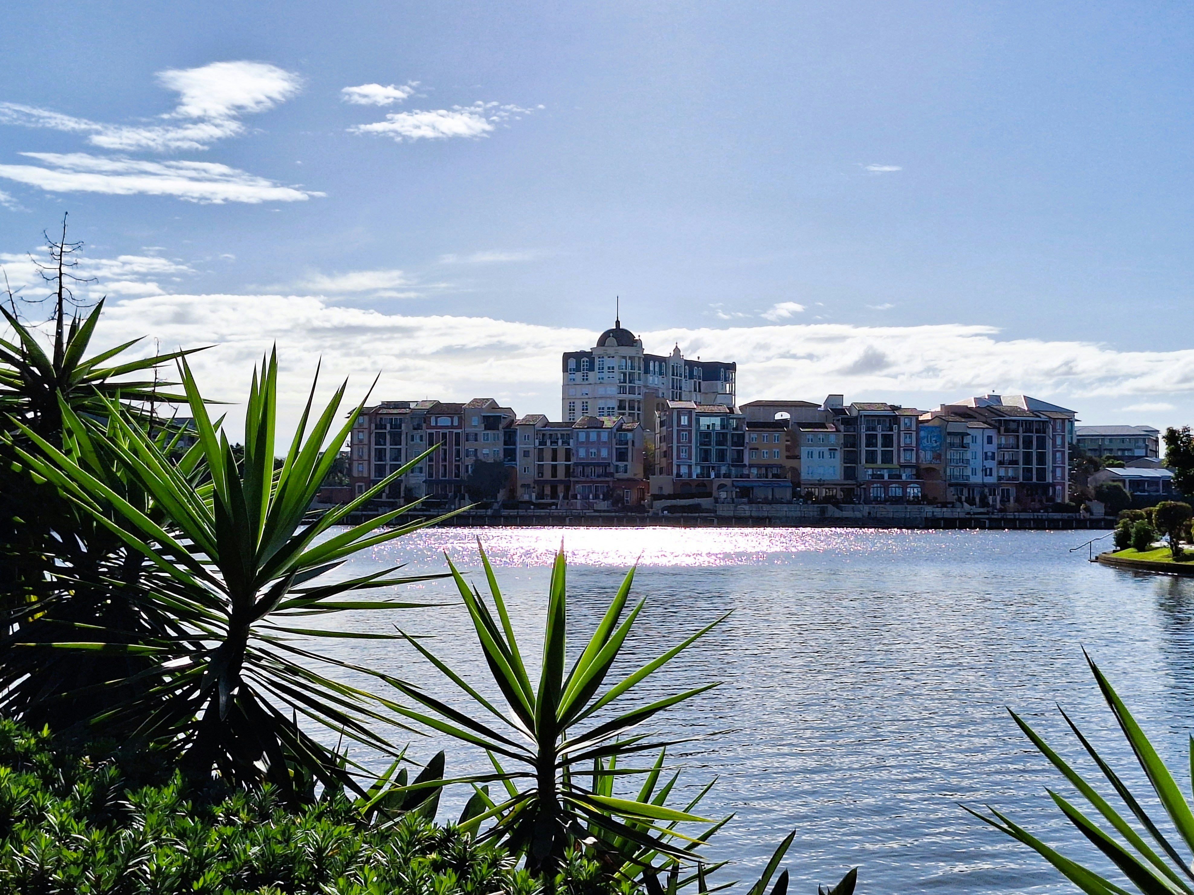 Cityscape beside a lake under a bright, sunny sky.
