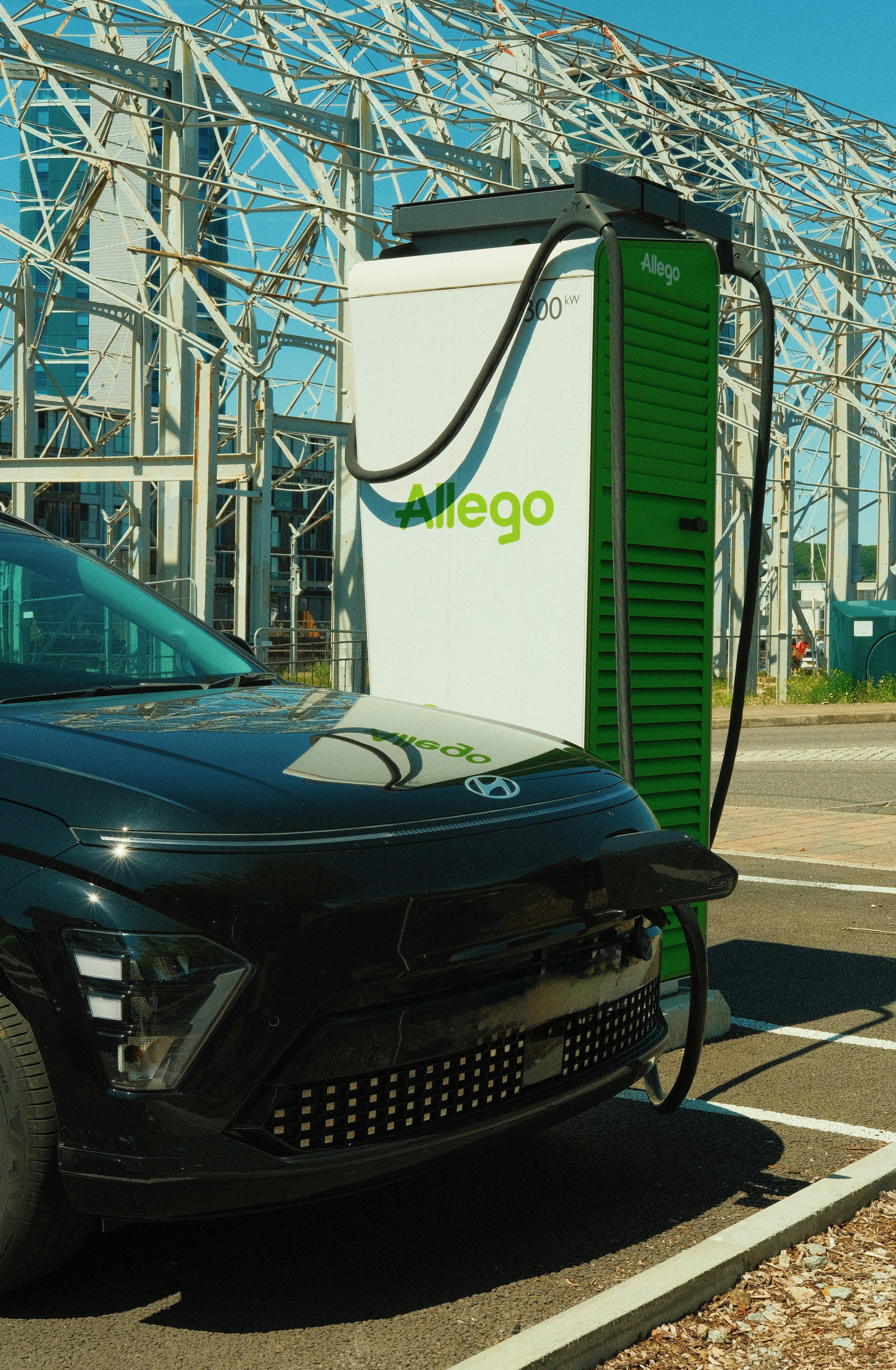 Black electric vehicle parked at a high-speed charging station with an Allego logo in the background.