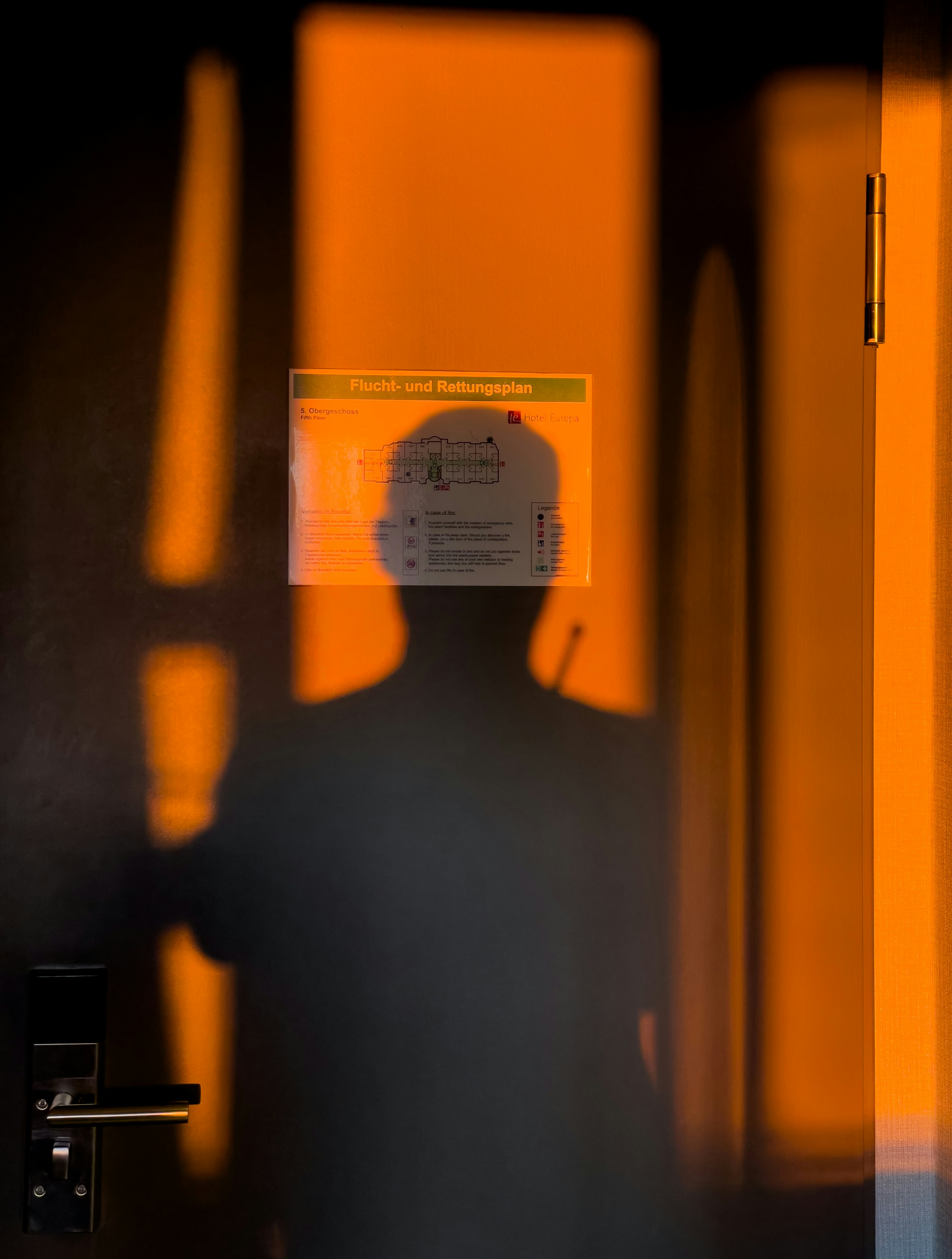 Amber Shadow: Silhouette on a Door Beneath an Emergency Plan
