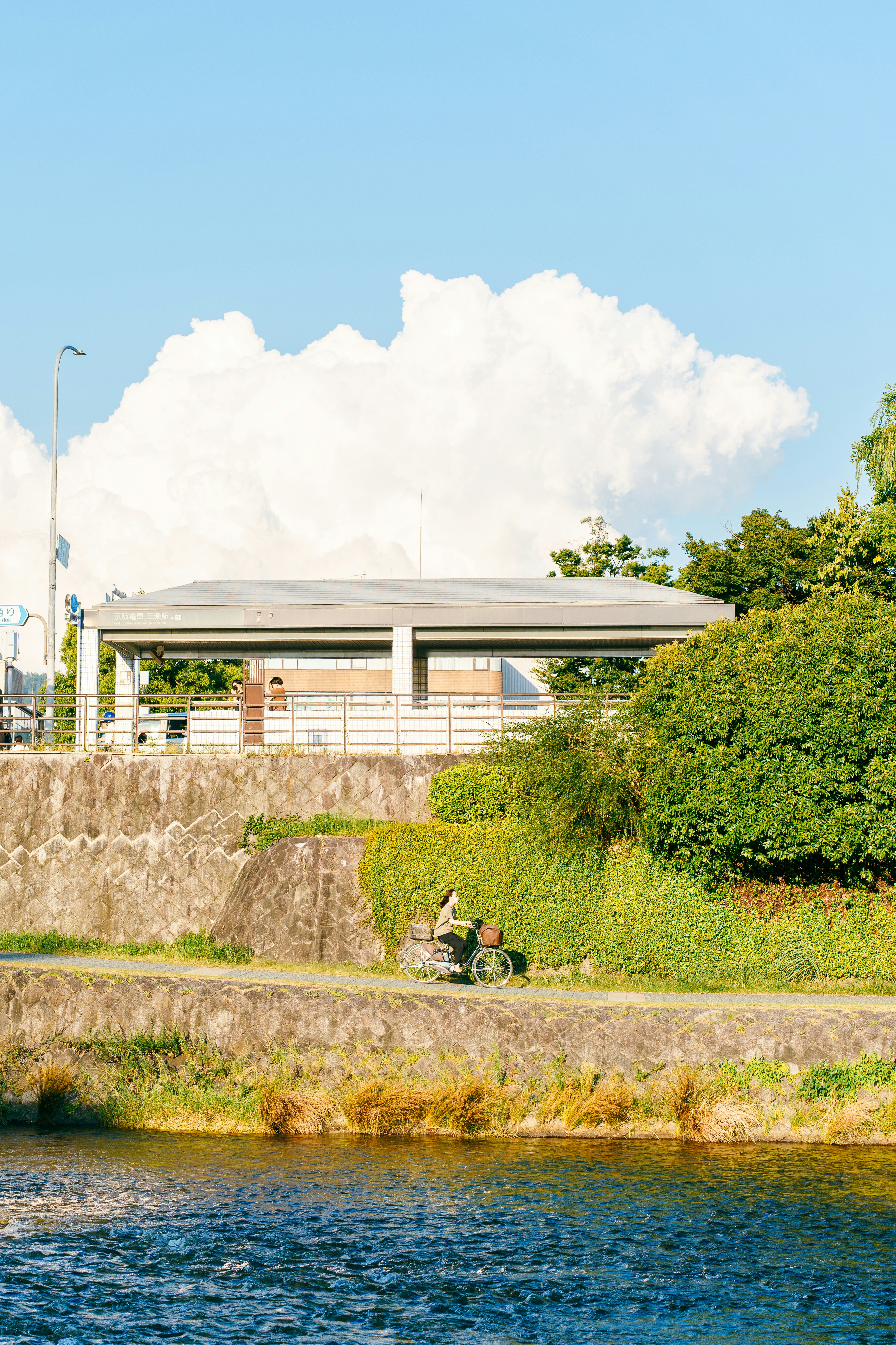 A person sits on a bench near a river.