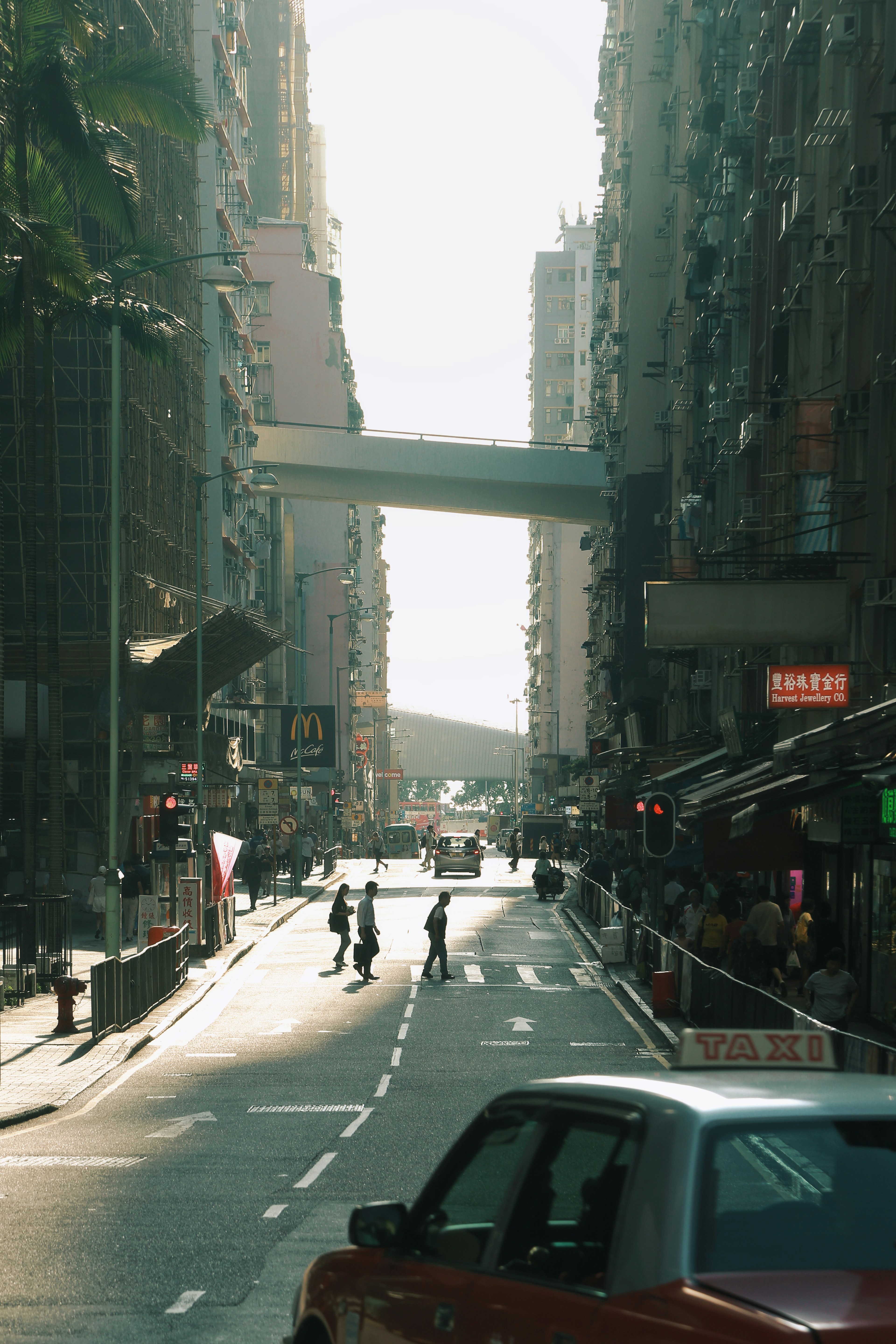 Urban street with tall buildings and a pedestrian bridge.