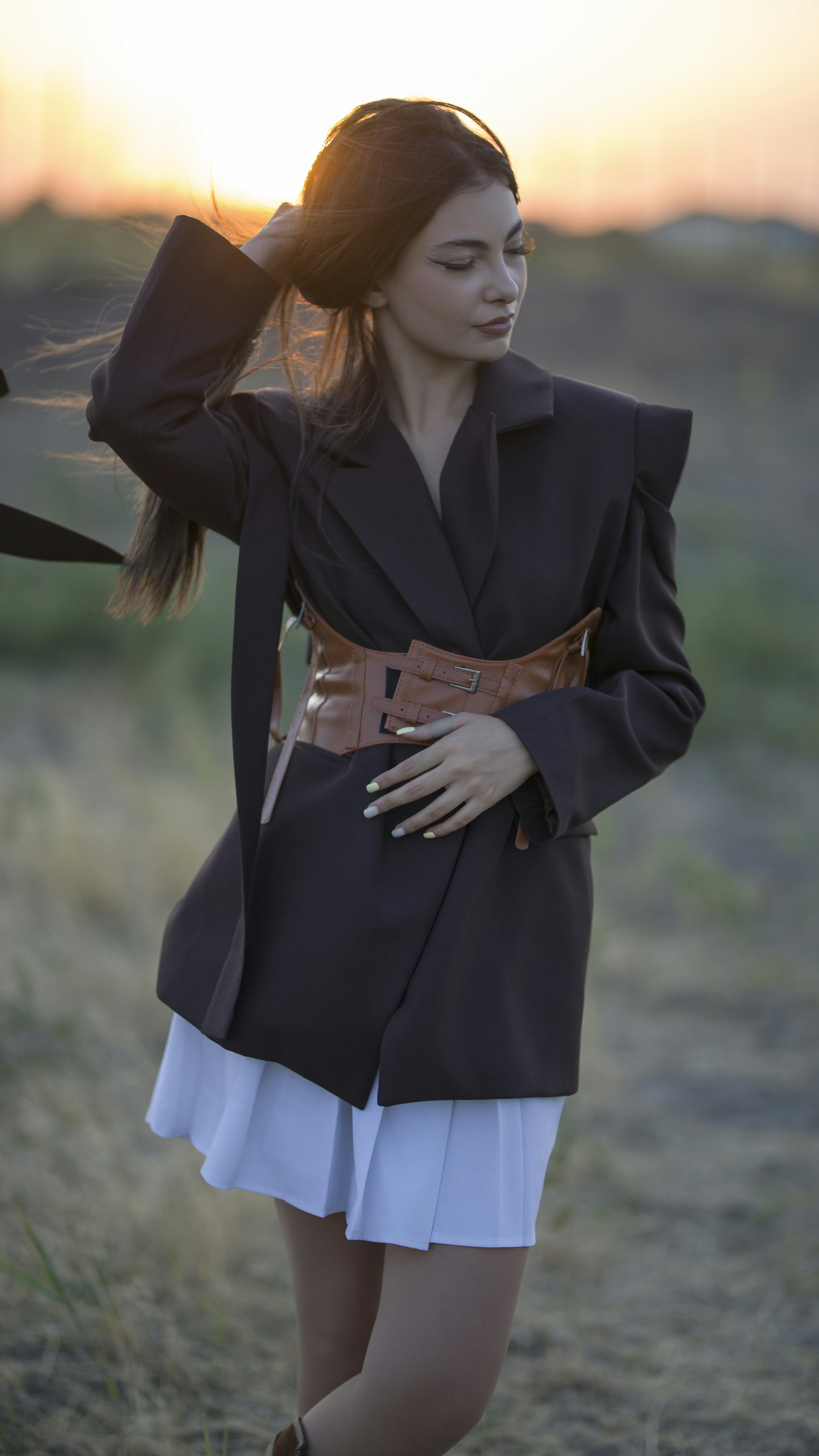 Woman posing in the sunset, wearing a blazer.