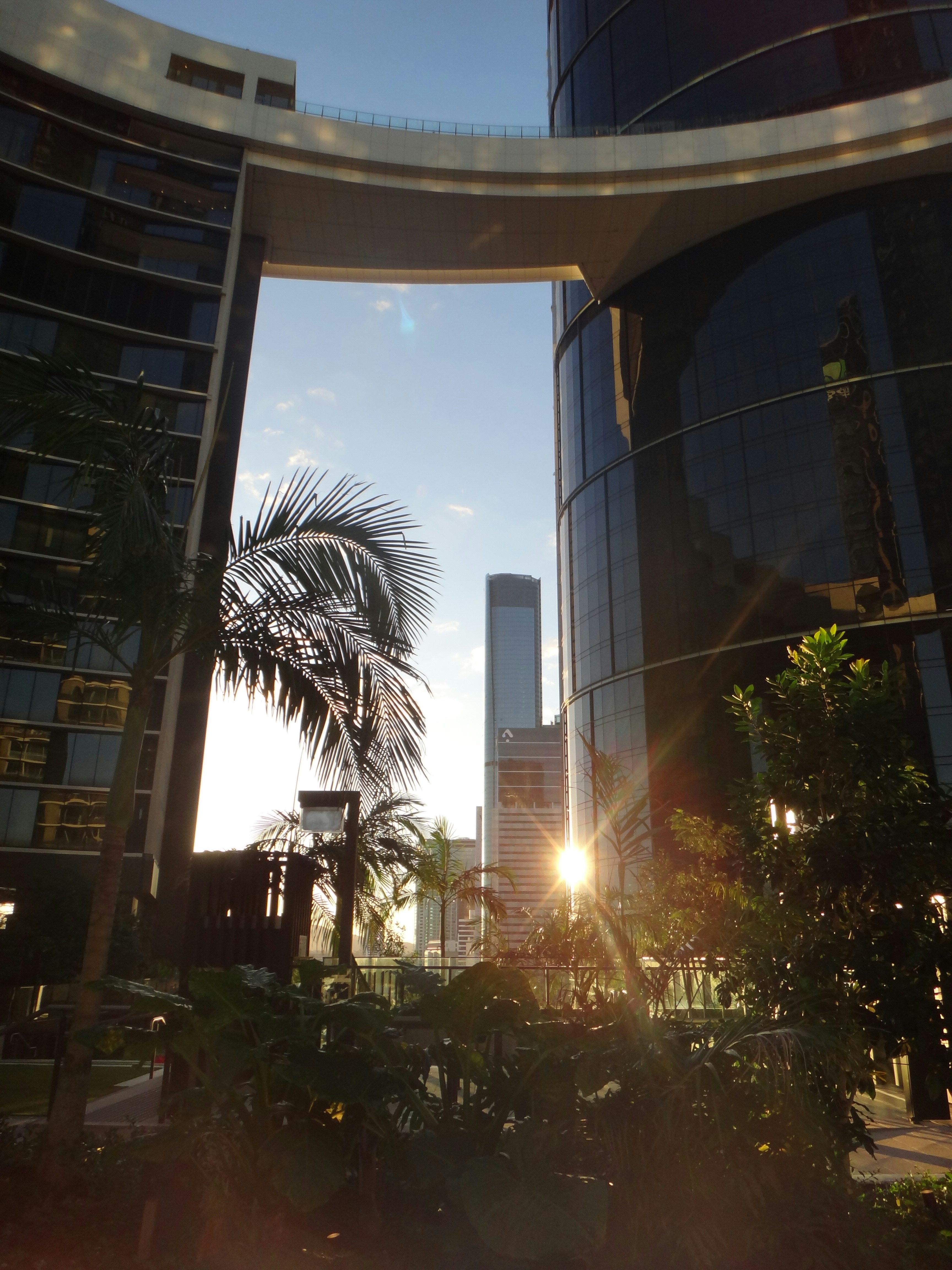 Sun shines through buildings and a bridge.