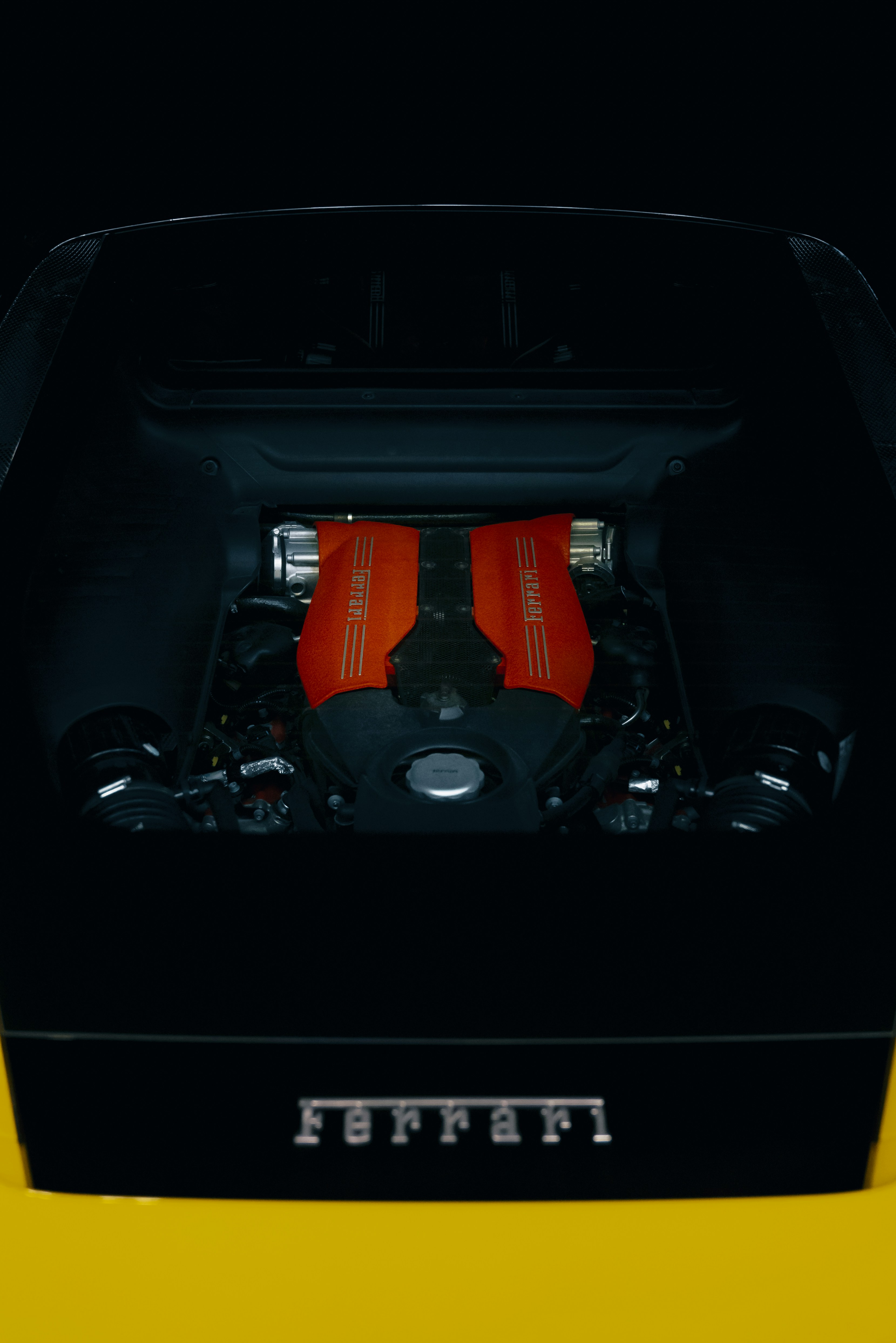 Close-up of a Ferrari engine showcasing its striking red components against a dark backdrop. The intricate engineering highlights the essence of automotive excellence.