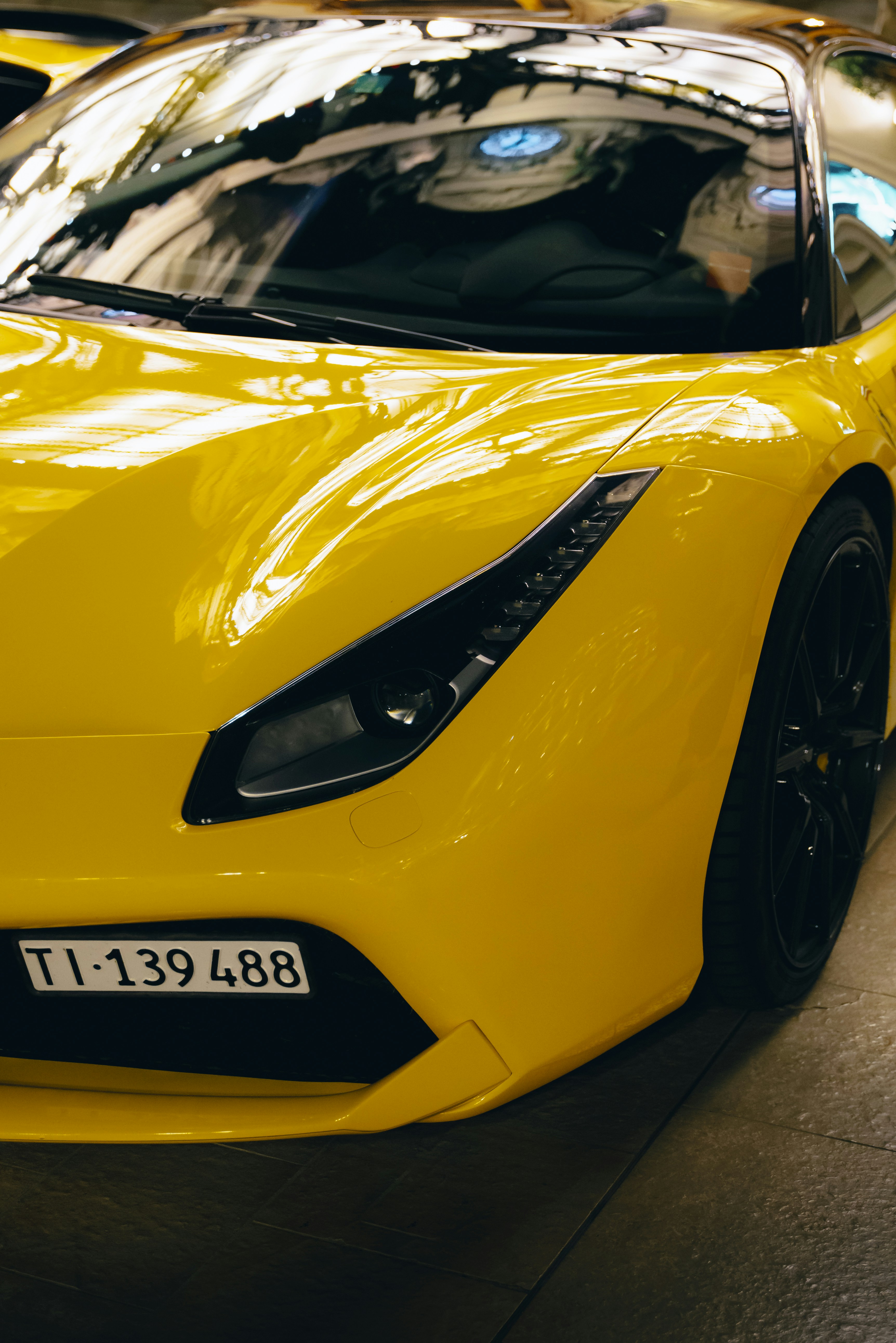 Close-up of a sleek yellow sports car showcasing its aerodynamic design and striking features, parked in a well-lit environment.