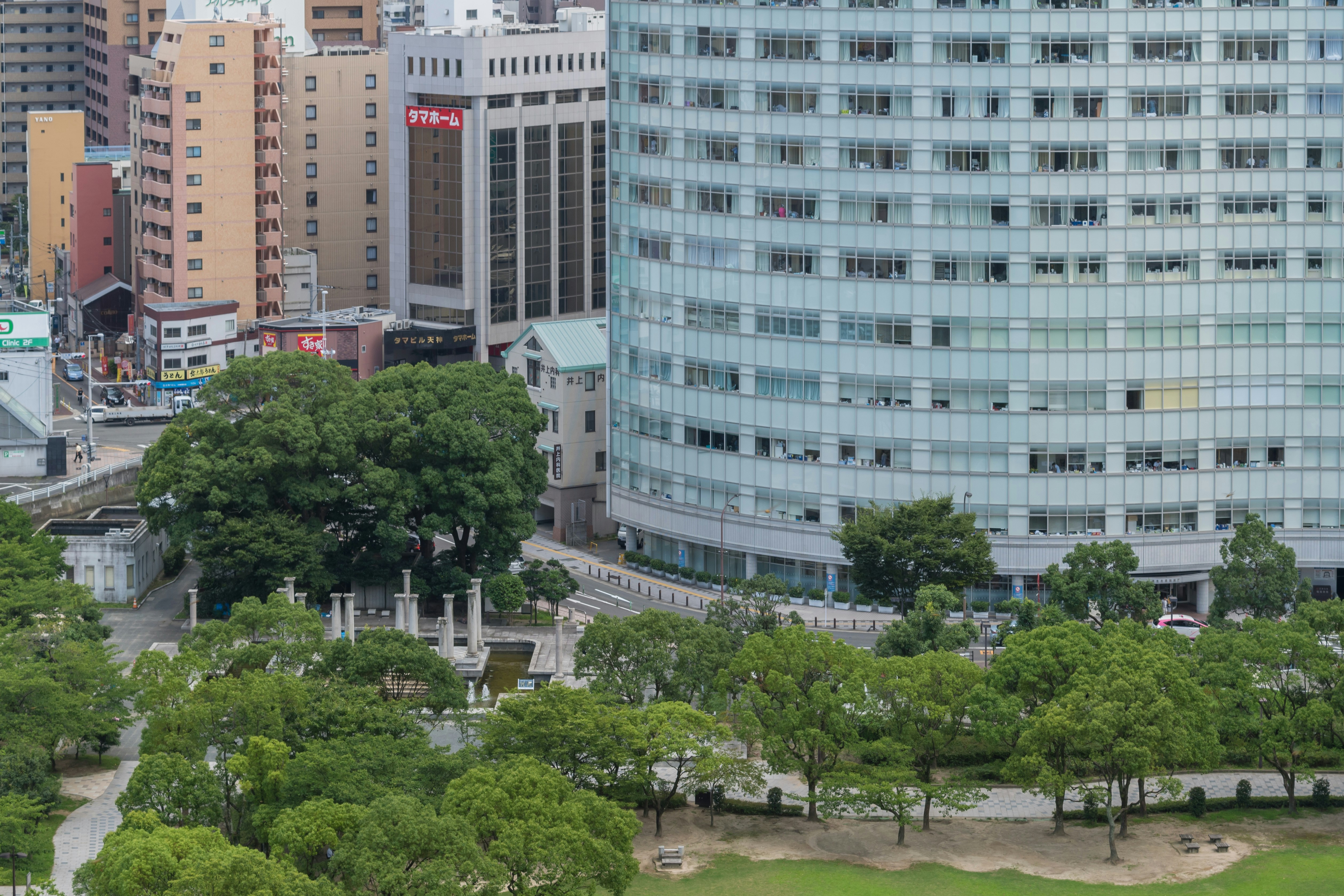 Cityscape with a tall, modern building and green spaces.