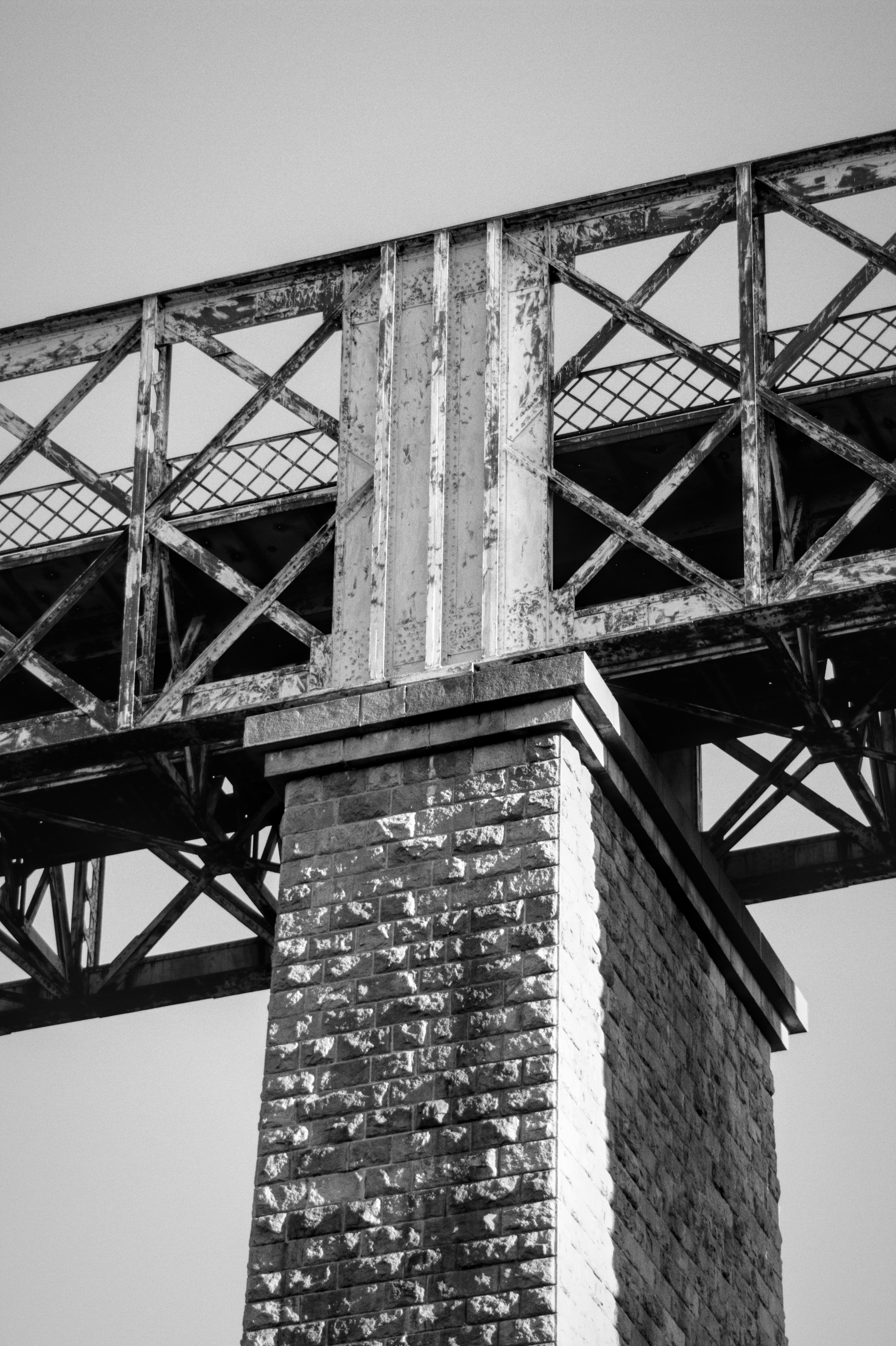 Weathered bridge supports showcasing intricate metalwork and aged stone textures against a clear sky.