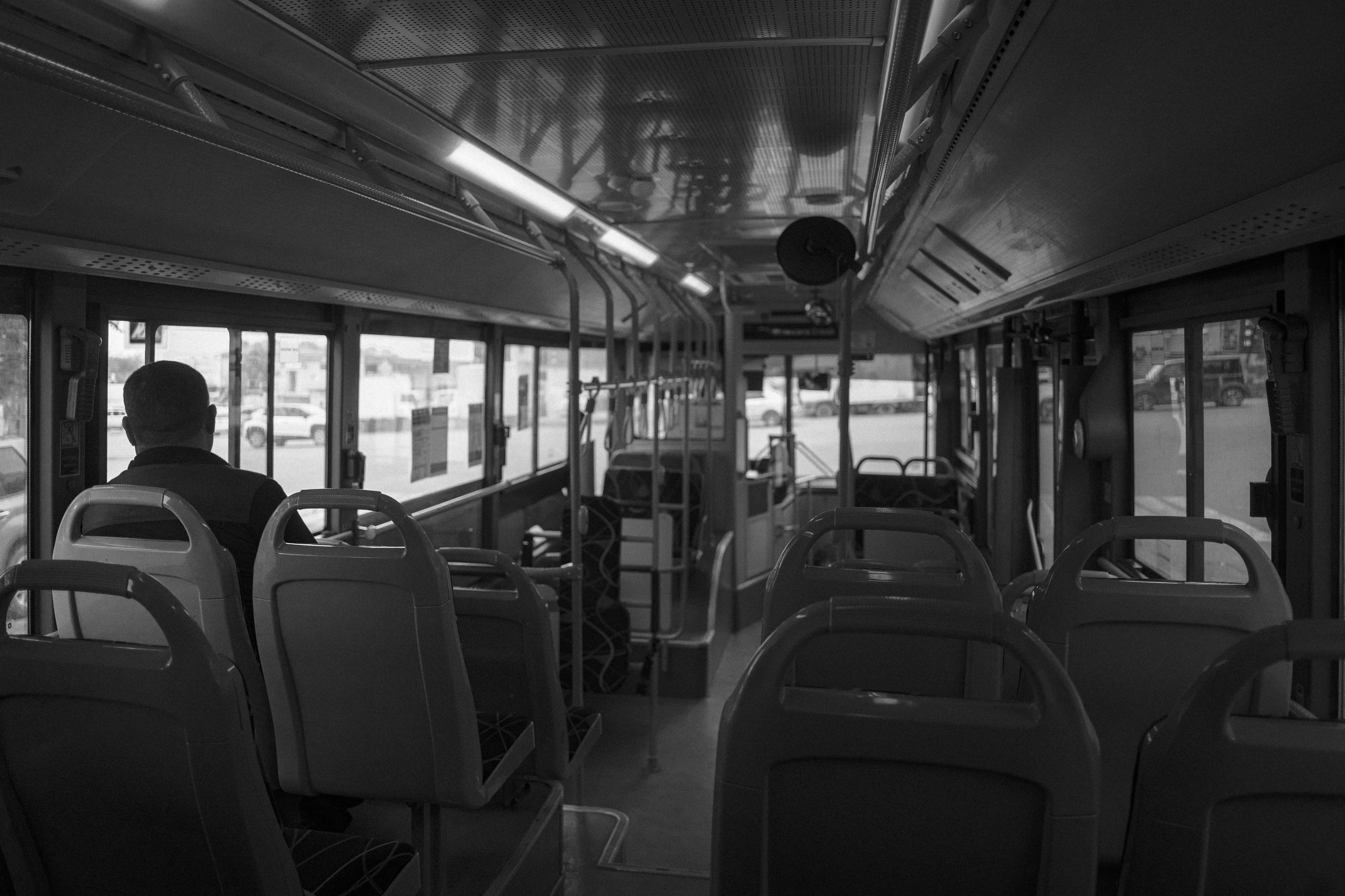 An empty bus with only one passenger | An empty bus interior with a lone passenger.