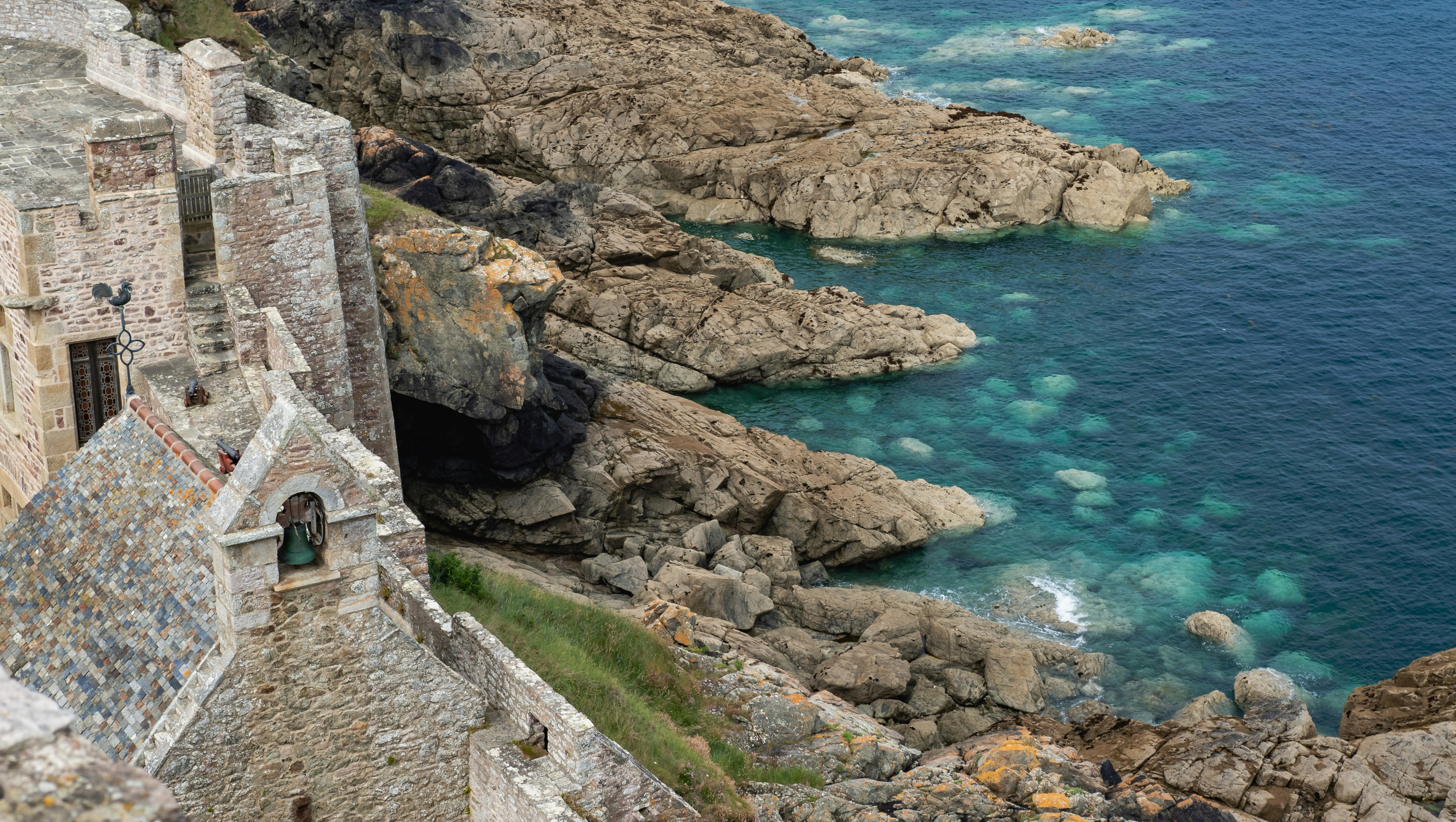 OLYMPUS DIGITAL CAMERA | Stone castle sits beside a rocky coastline.